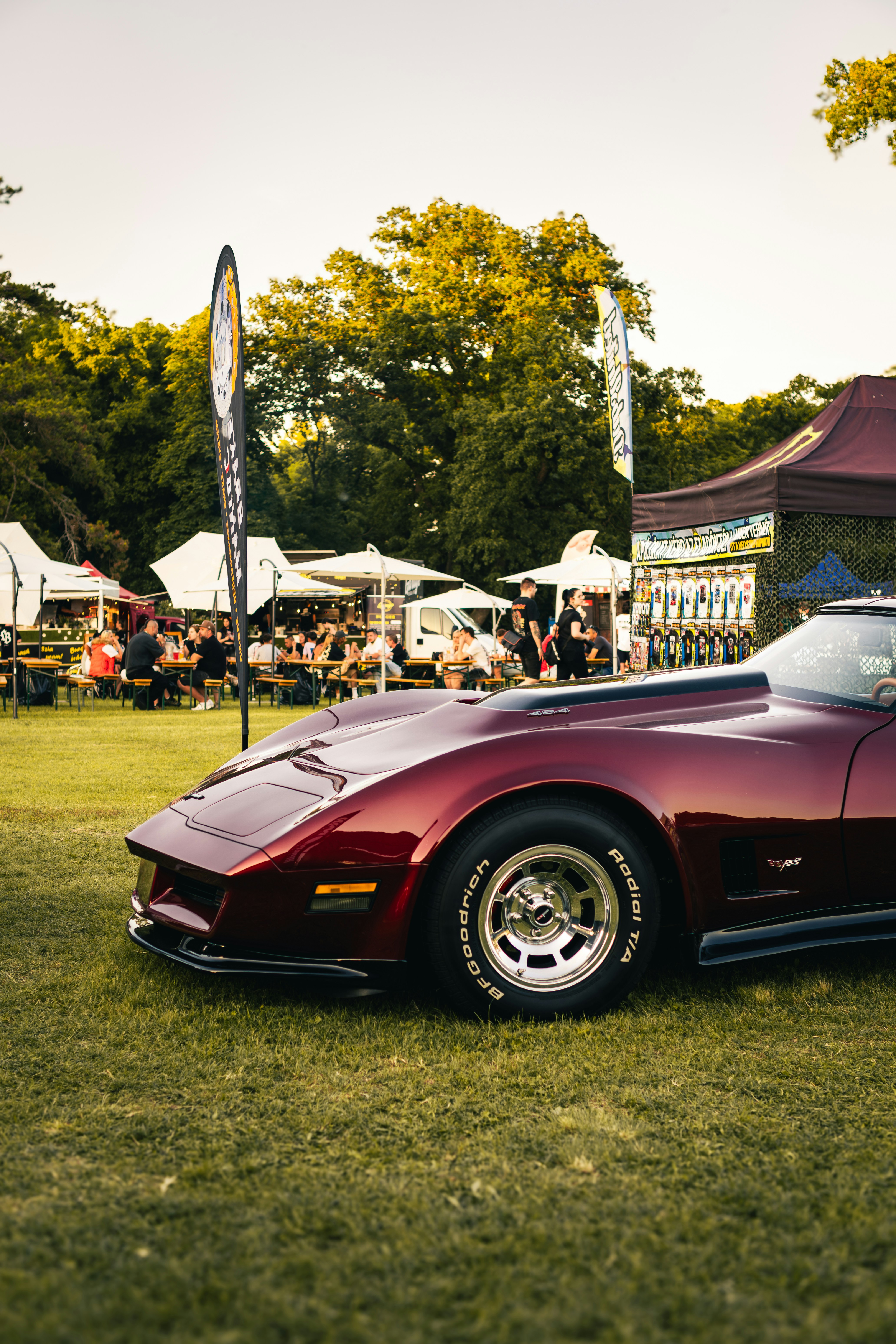 Crimson Corvette at a sunlit outdoor car show