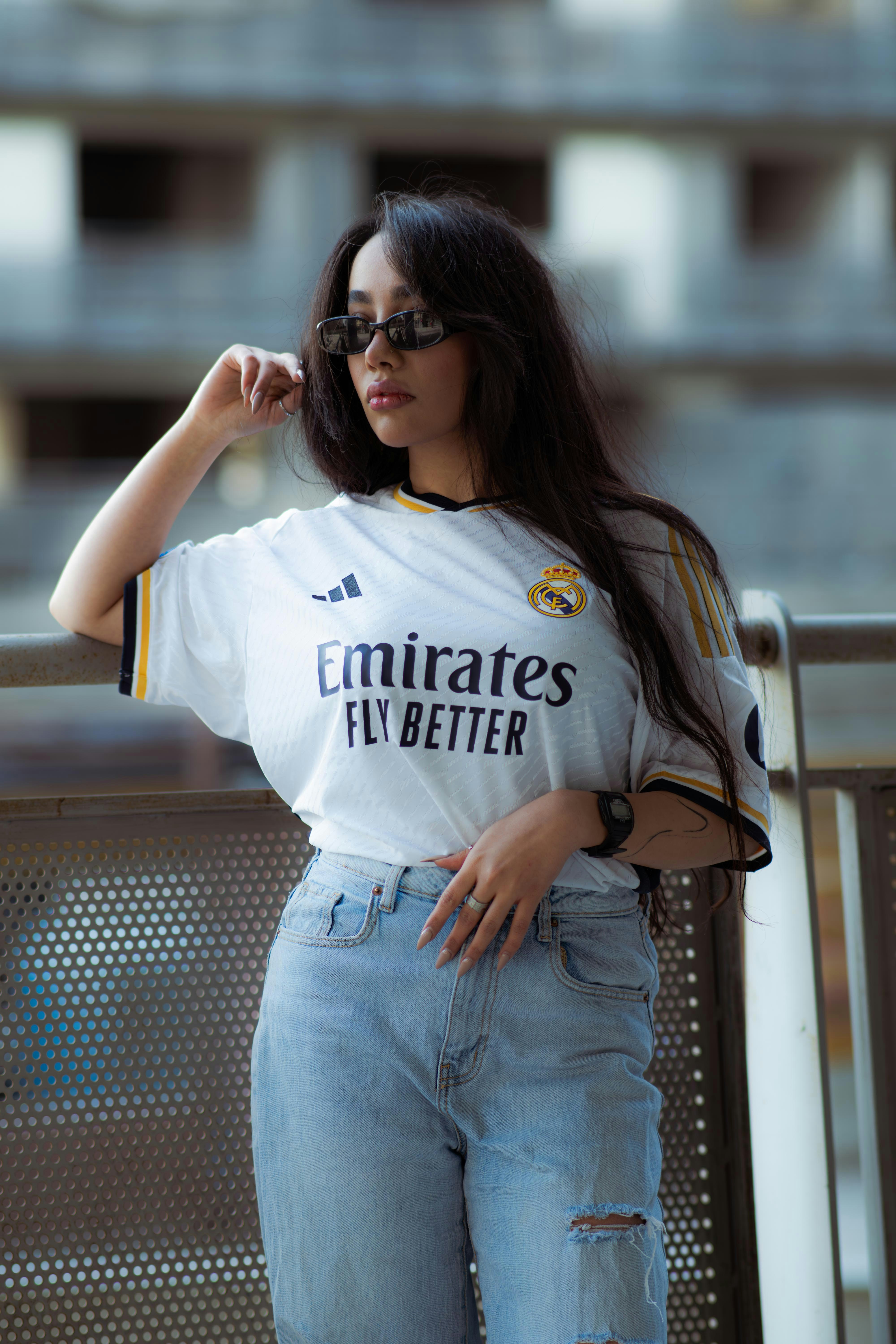 Woman in real madrid jersey and ripped jeans.
