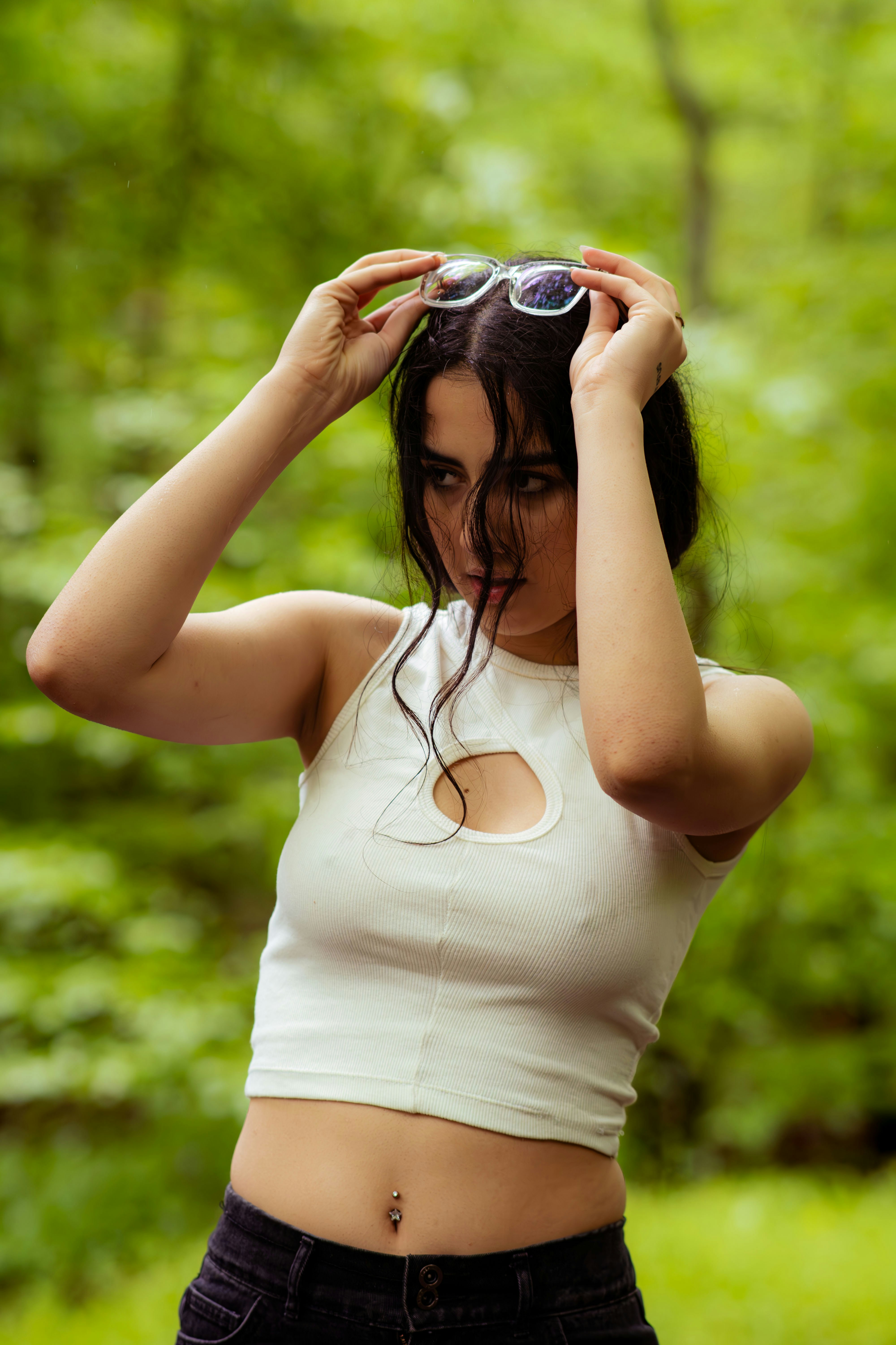 Woman adjusting sunglasses in a green forest