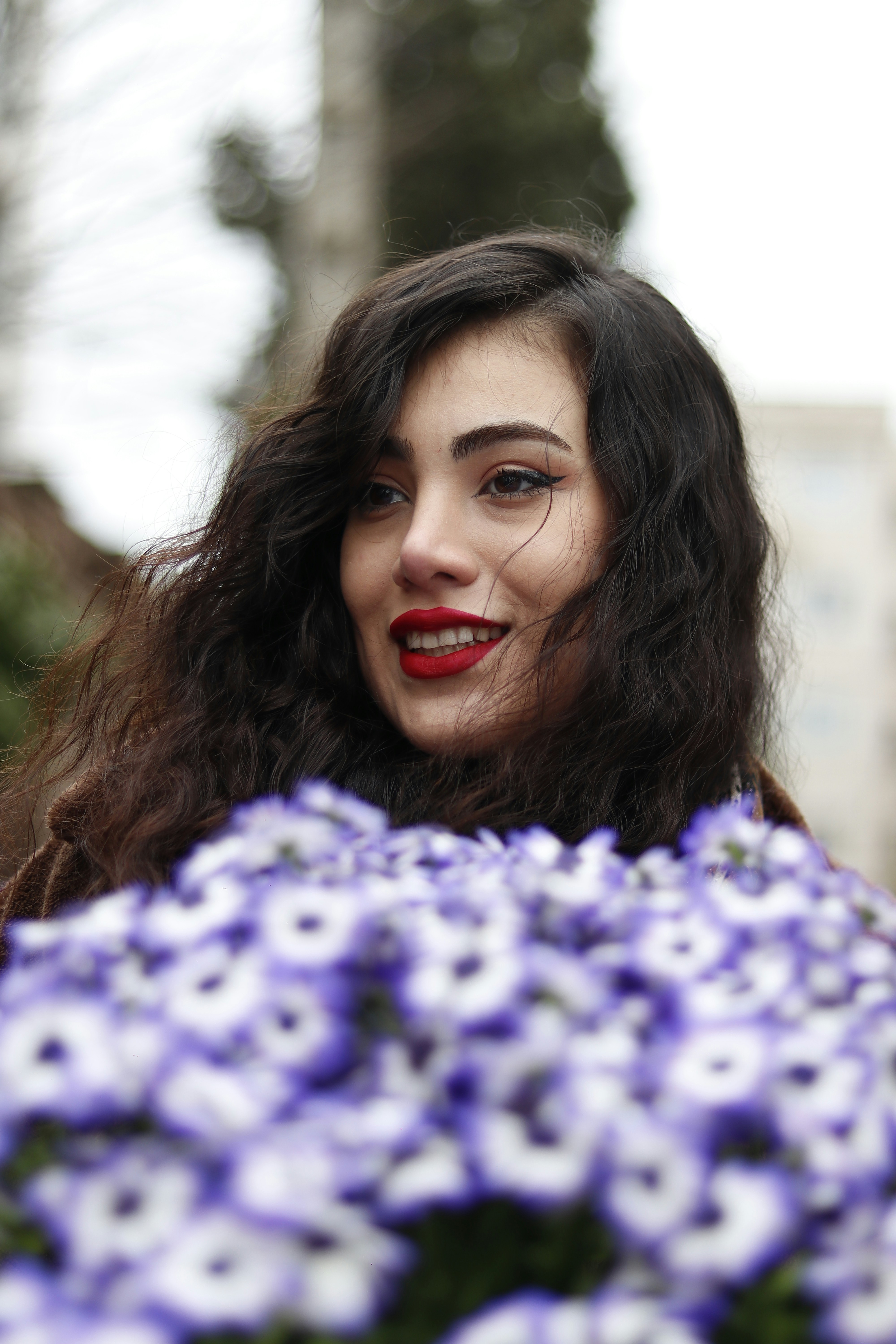 Crimson Smile Through a Sea of Violet: A Portrait Framed by Blooms