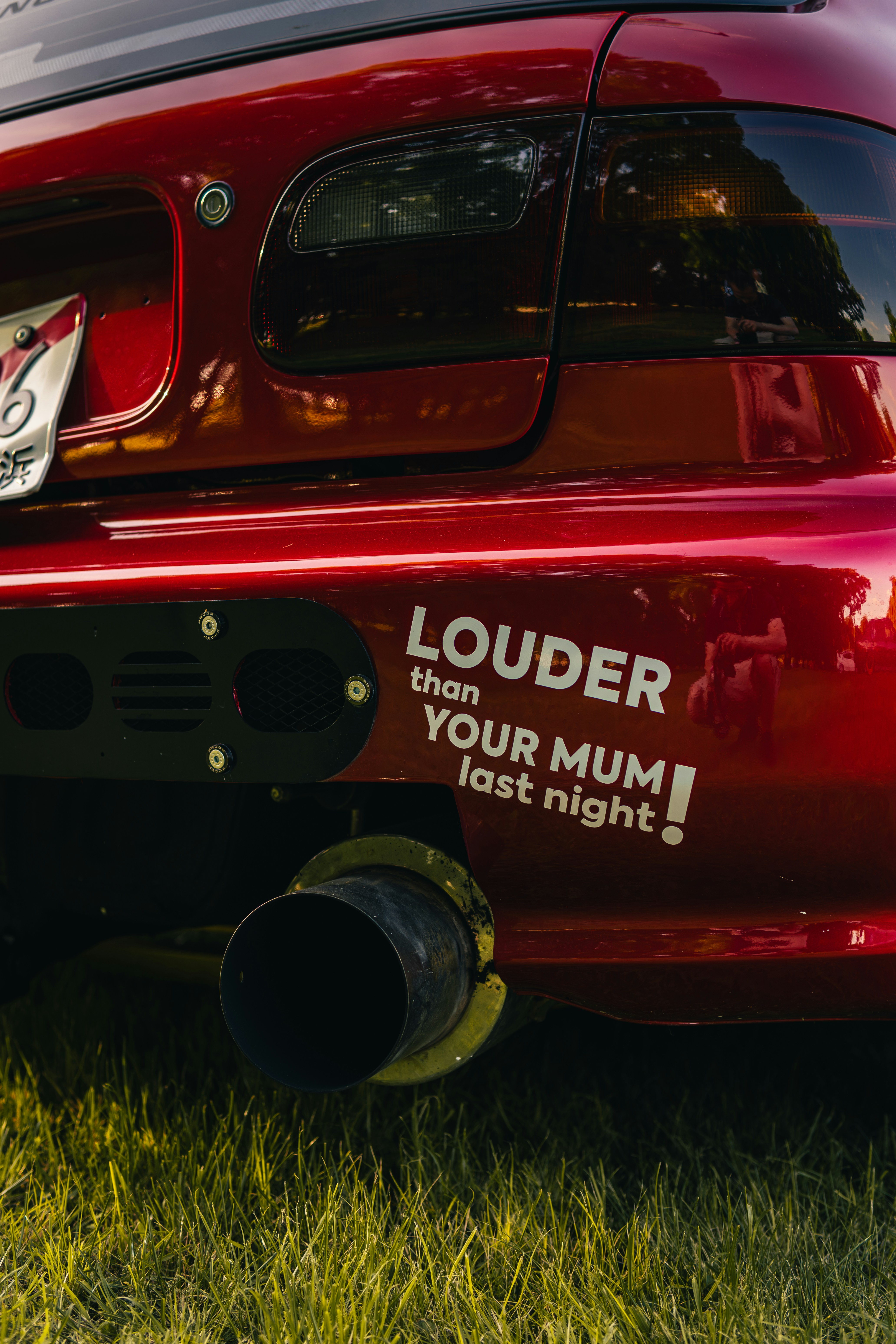 Louder Than Your Mum: A Cheeky Sticker on a Crimson Coupe