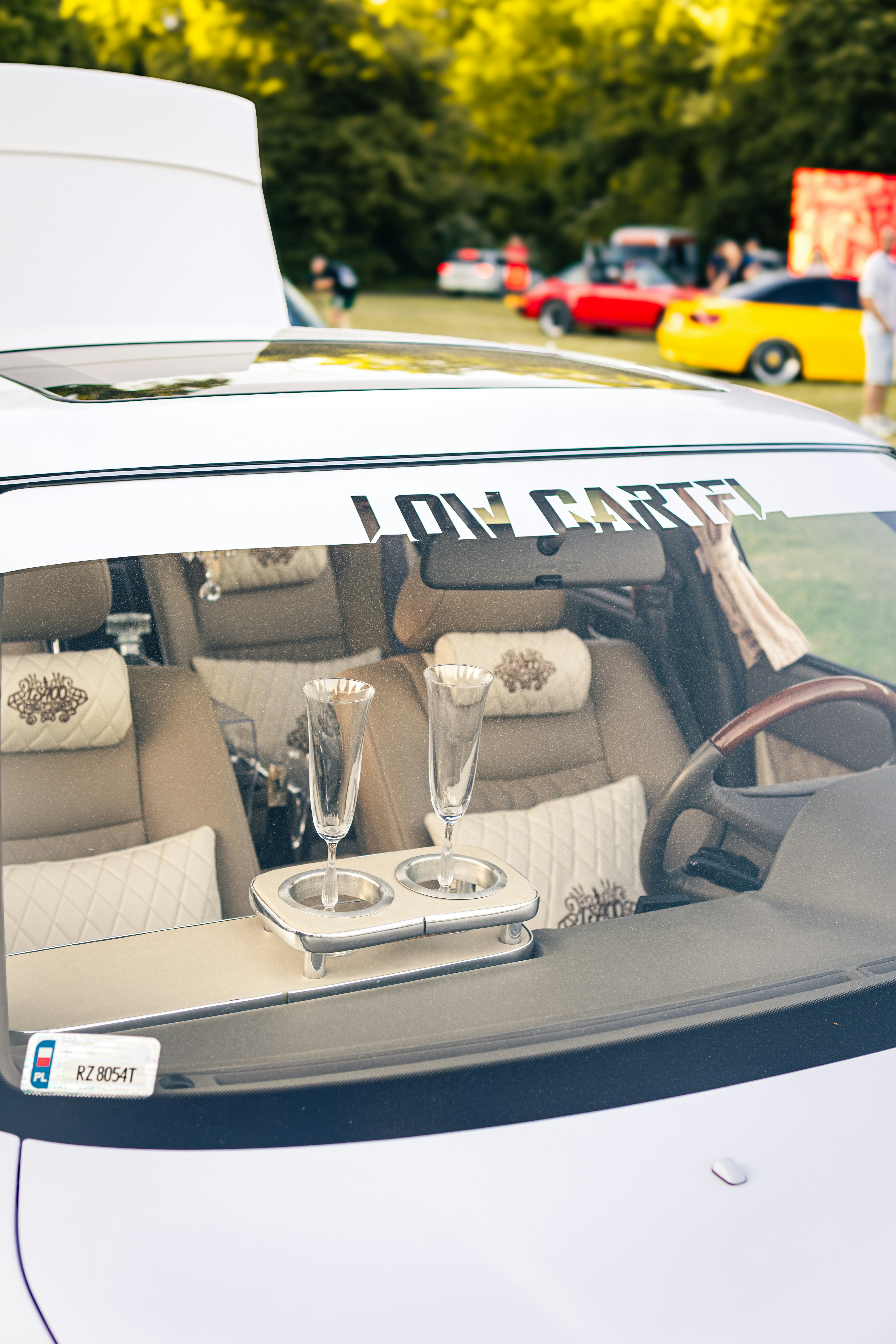 Champagne on Chrome: A Luxe Moment Inside a White Luxury Car at a Show