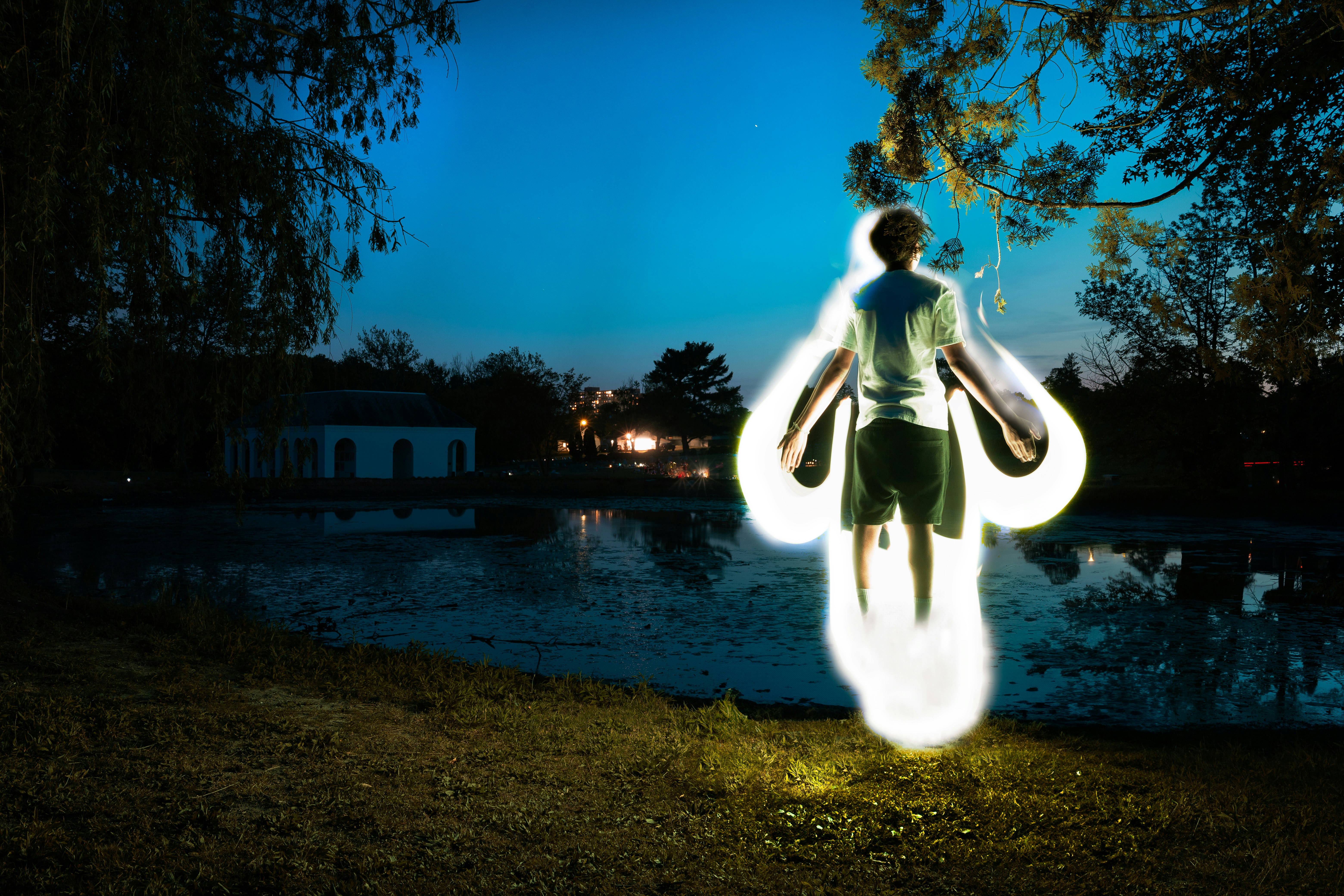 Persona brillando con luz cerca de un lago por la noche foto – Imagen ...