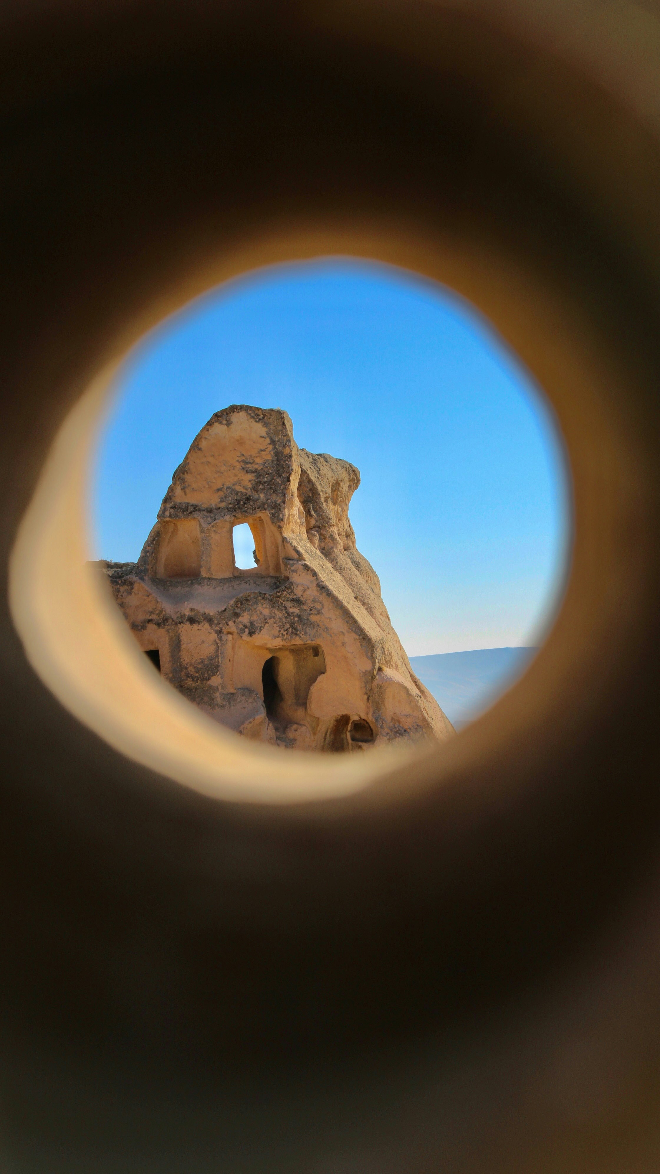 Ancient cave dwellings viewed through a circular opening.