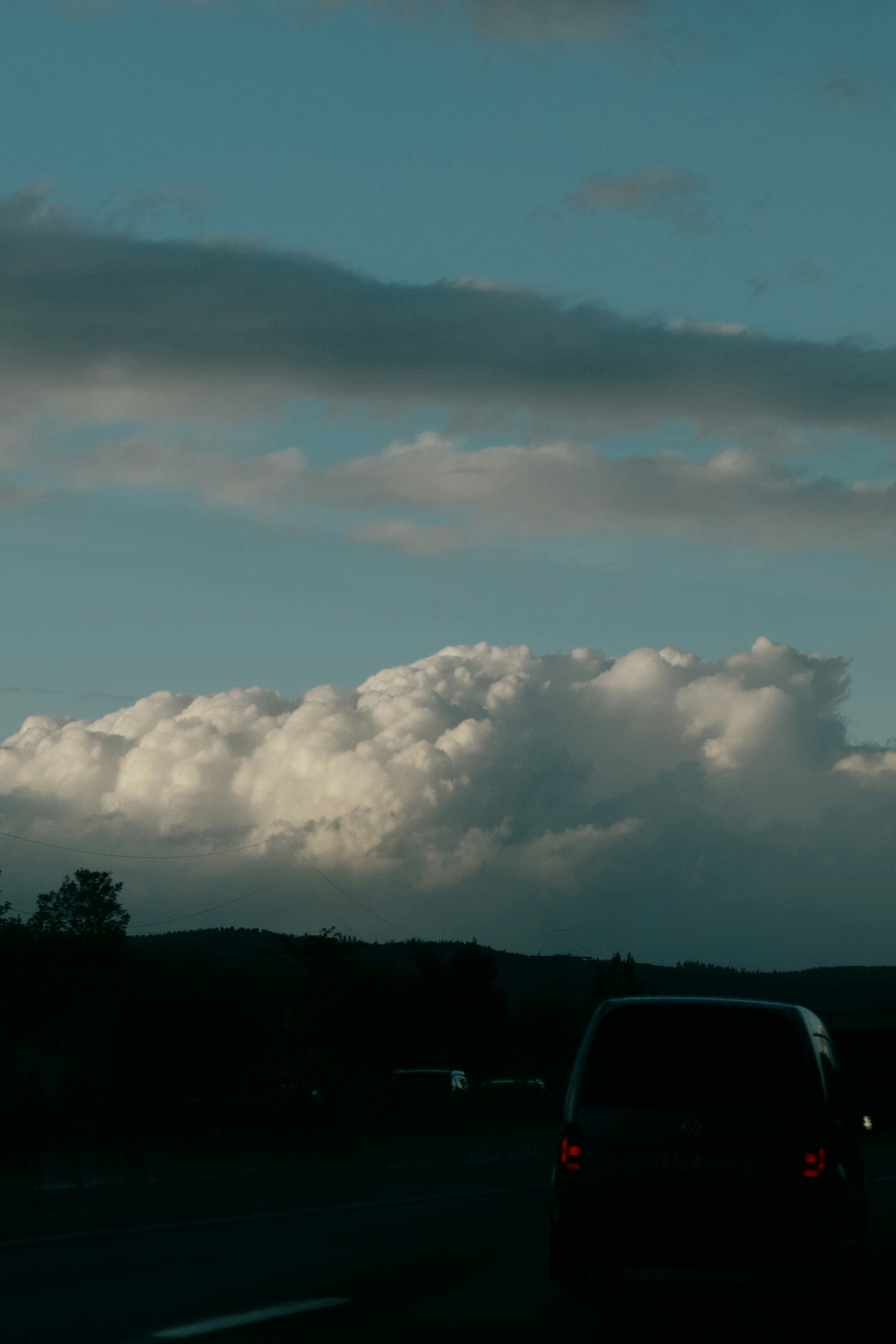 Clouds over a dark landscape with a car.