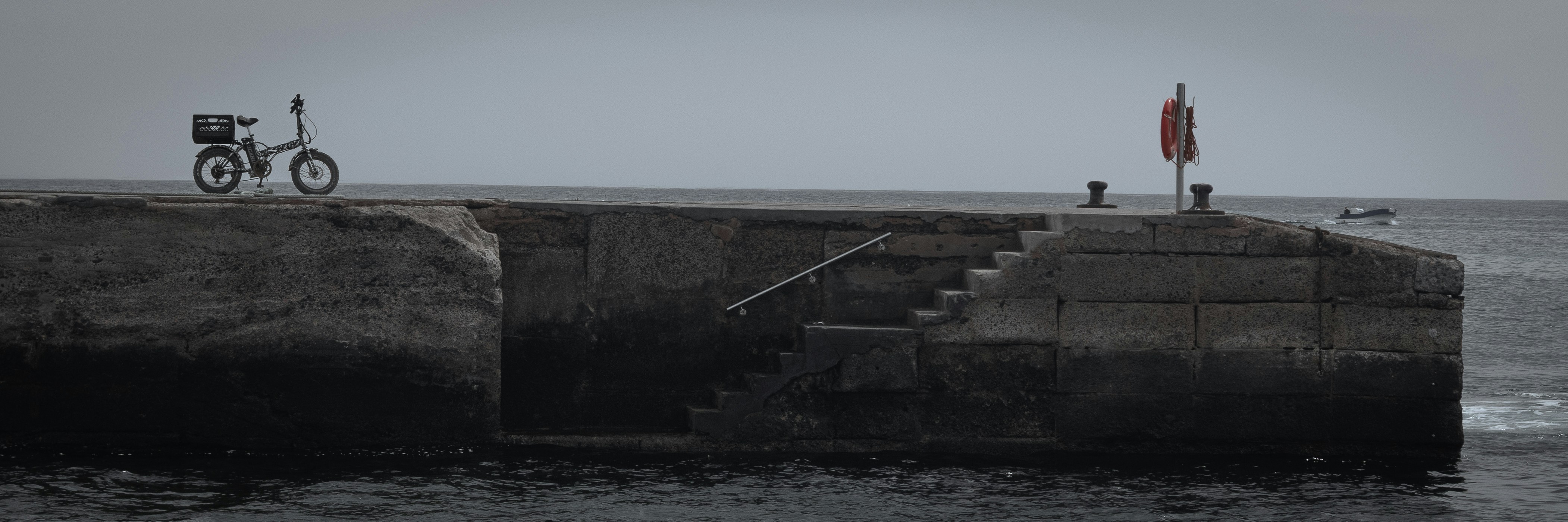 A bike on a lonely pier | A bicycle sits on a concrete pier by the ocean.