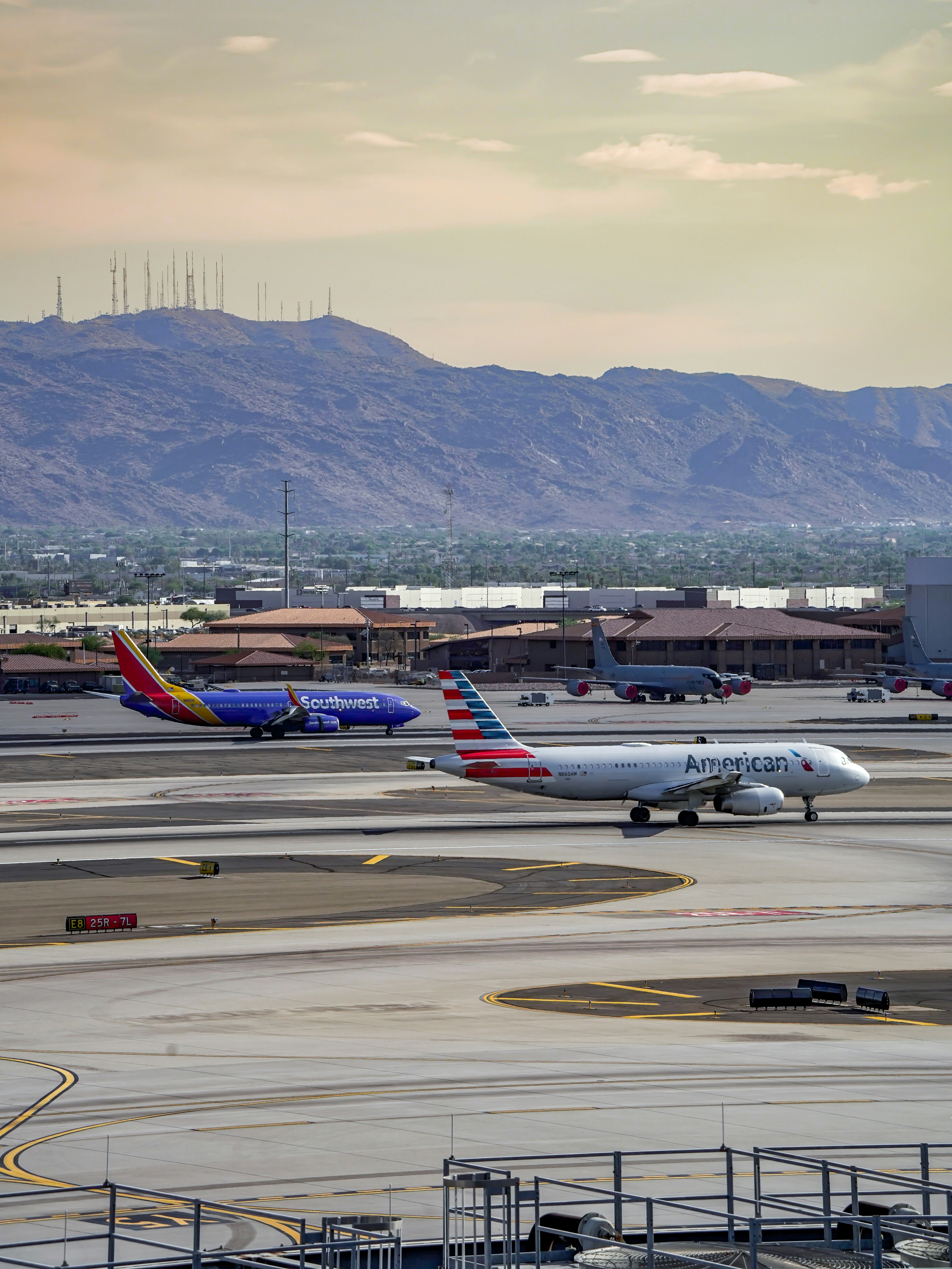 American Airlines aircraft taxiing on the runway with Southwest Airlines in the background, framed by a mountainous landscape.