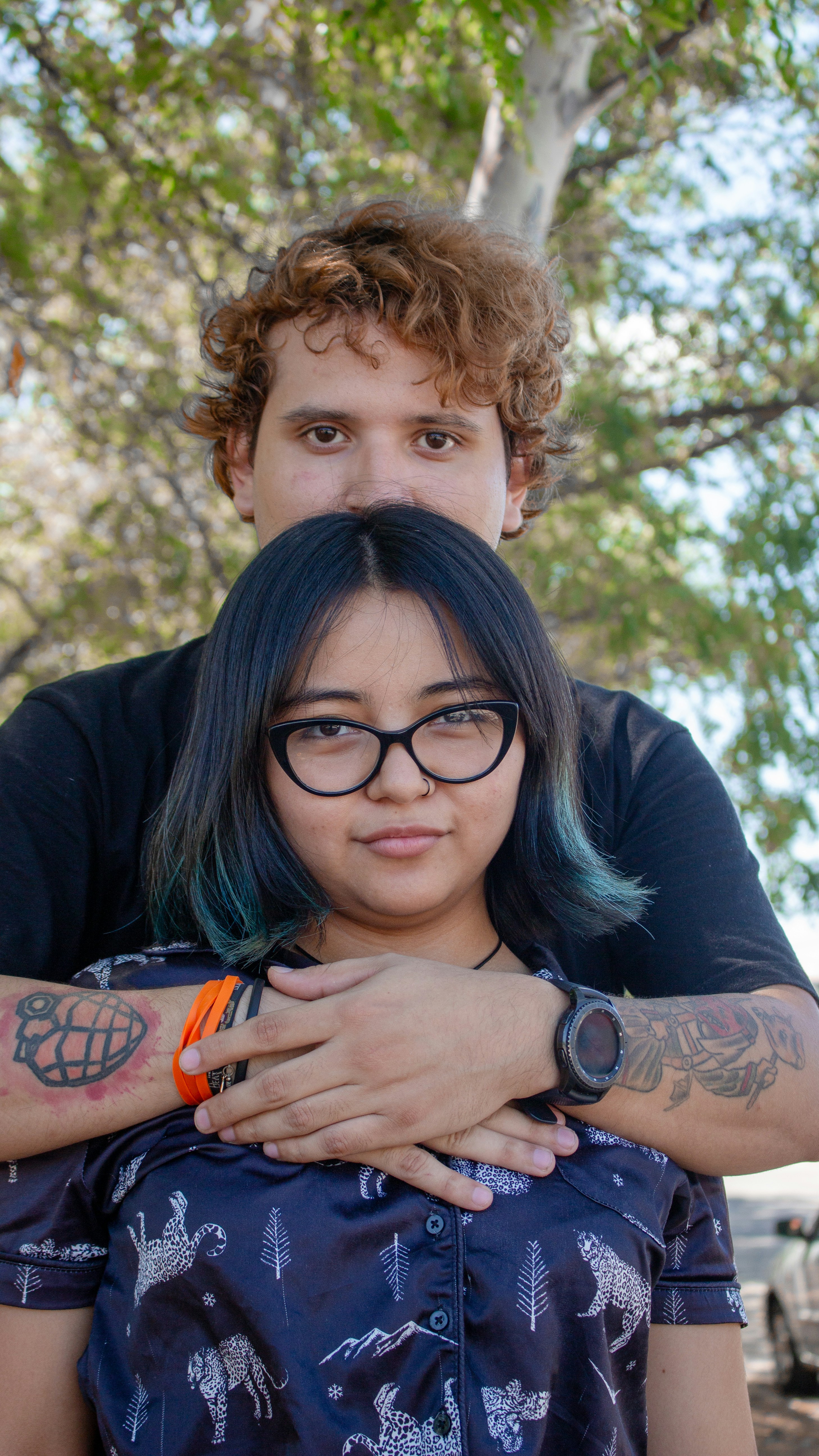 A man hugs a woman from behind outdoors
