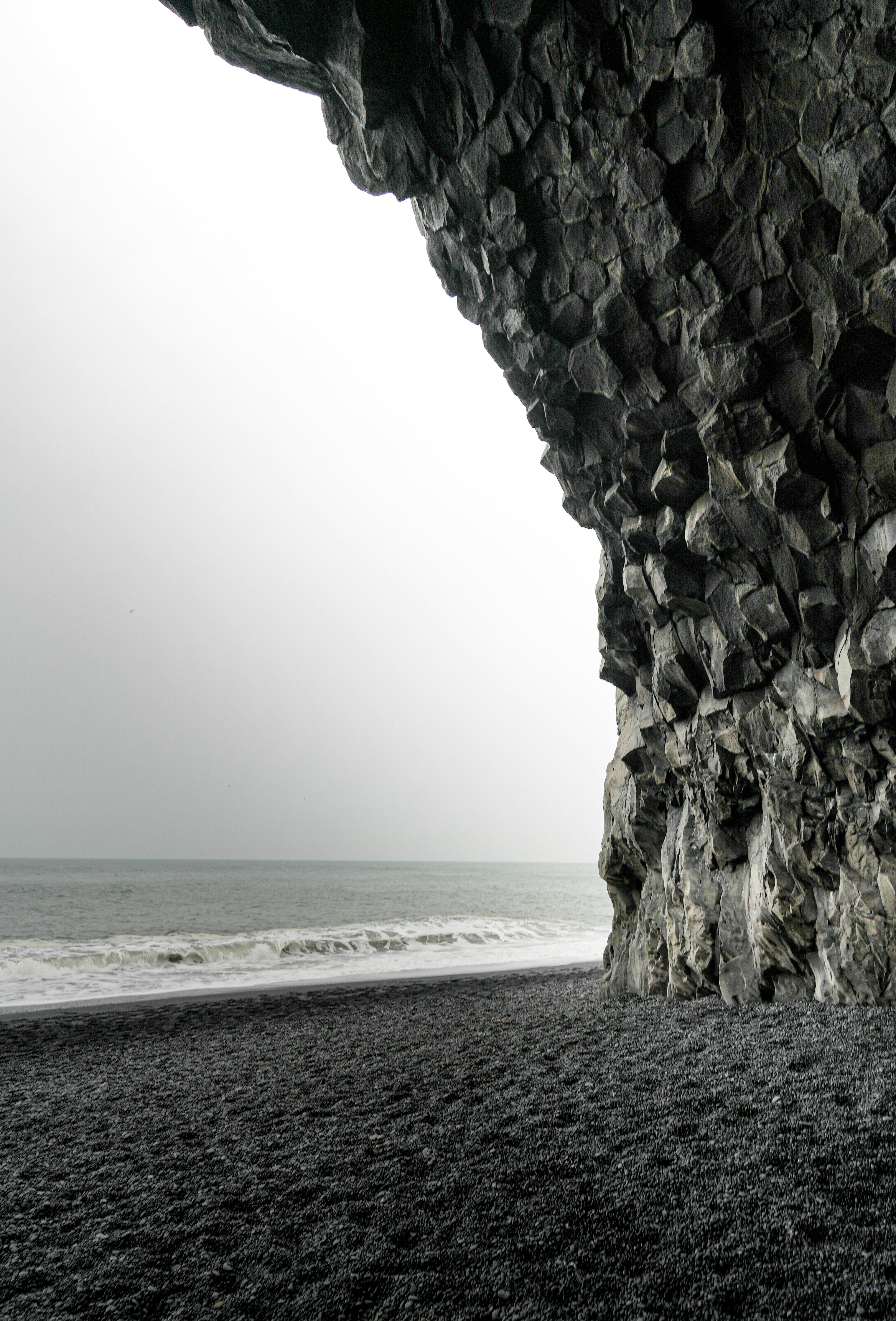 Rocky cave entrance overlooking a black sand beach