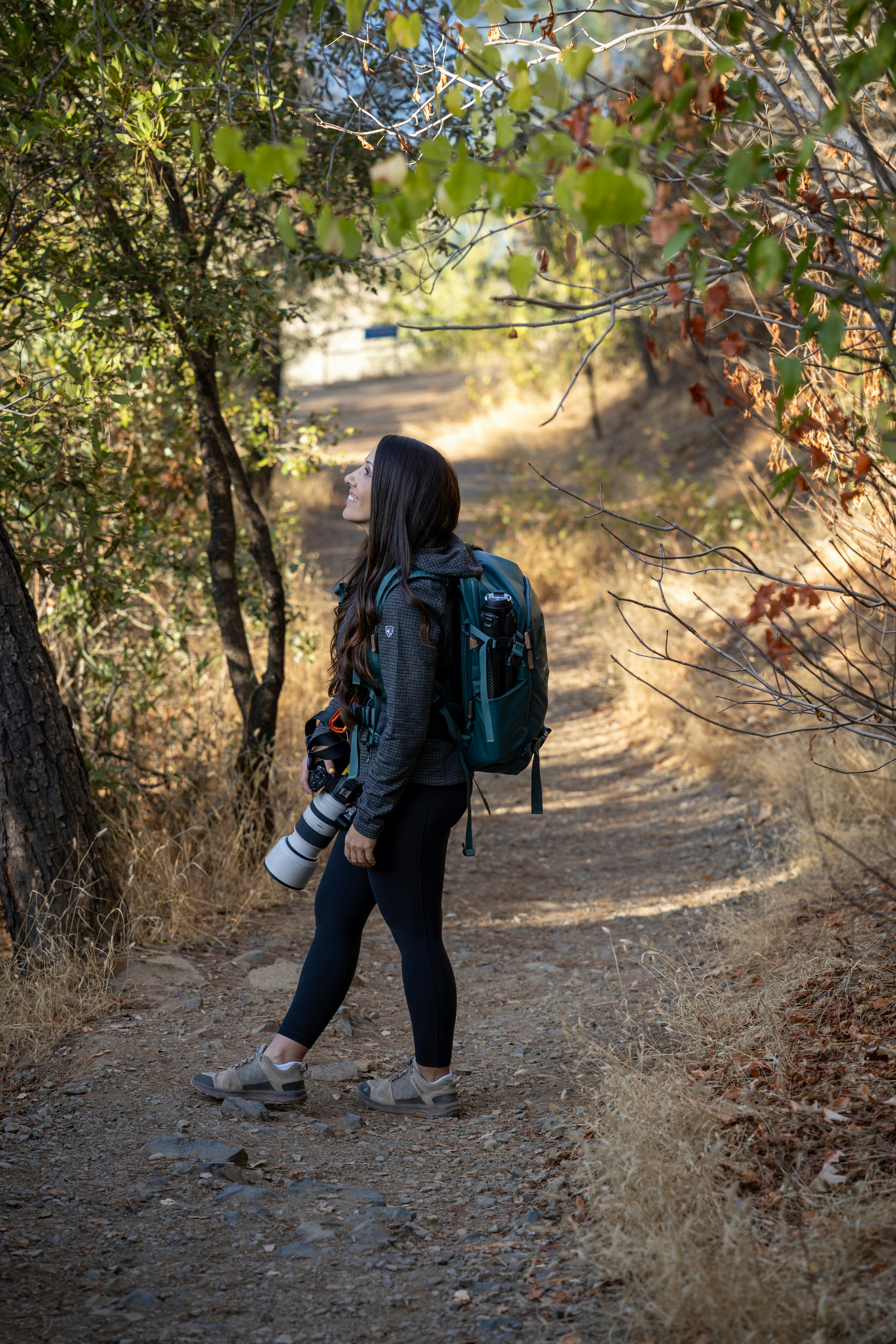 Woman with camera and backpack on a forest path