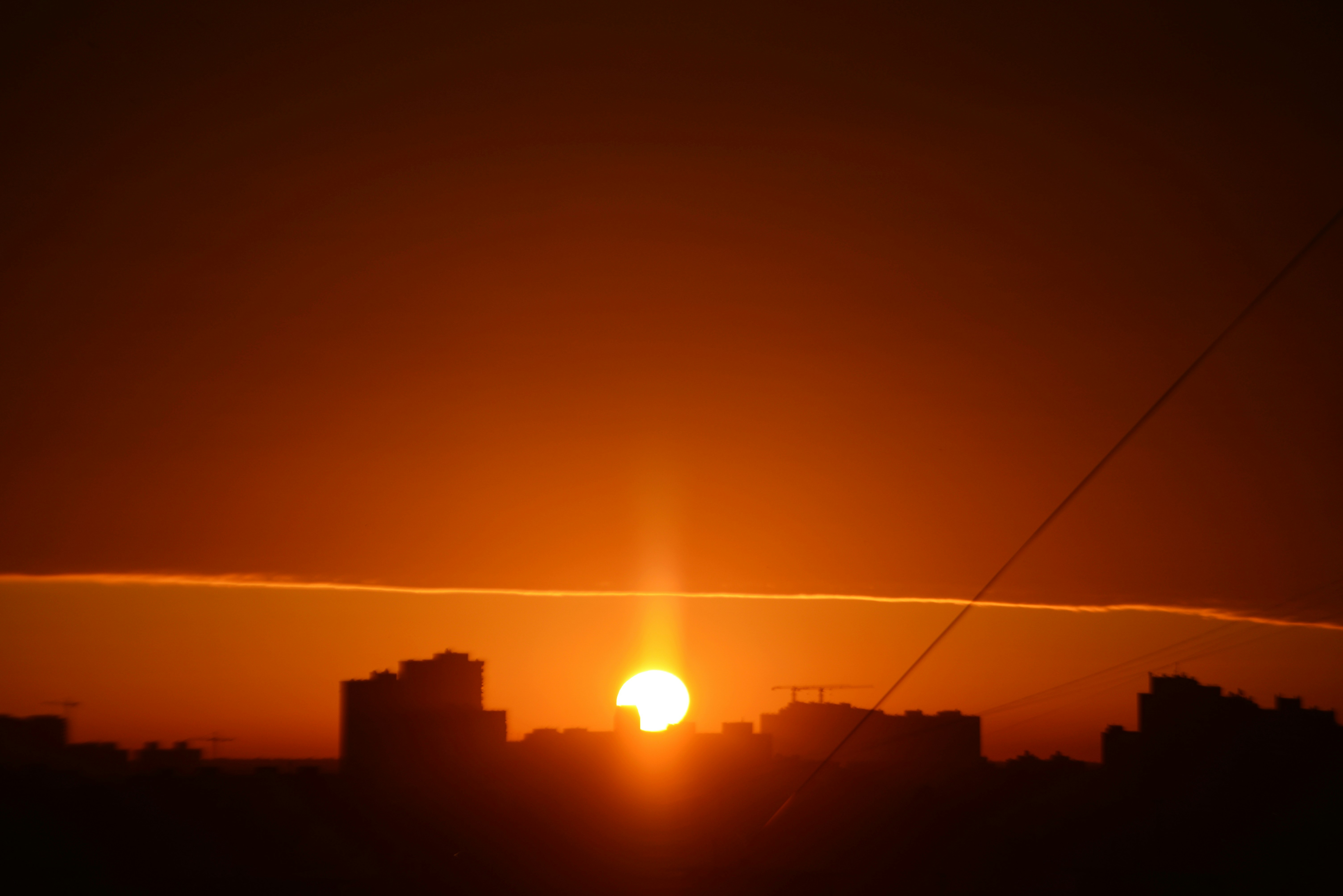 Sunset over a silhouetted cityscape with buildings