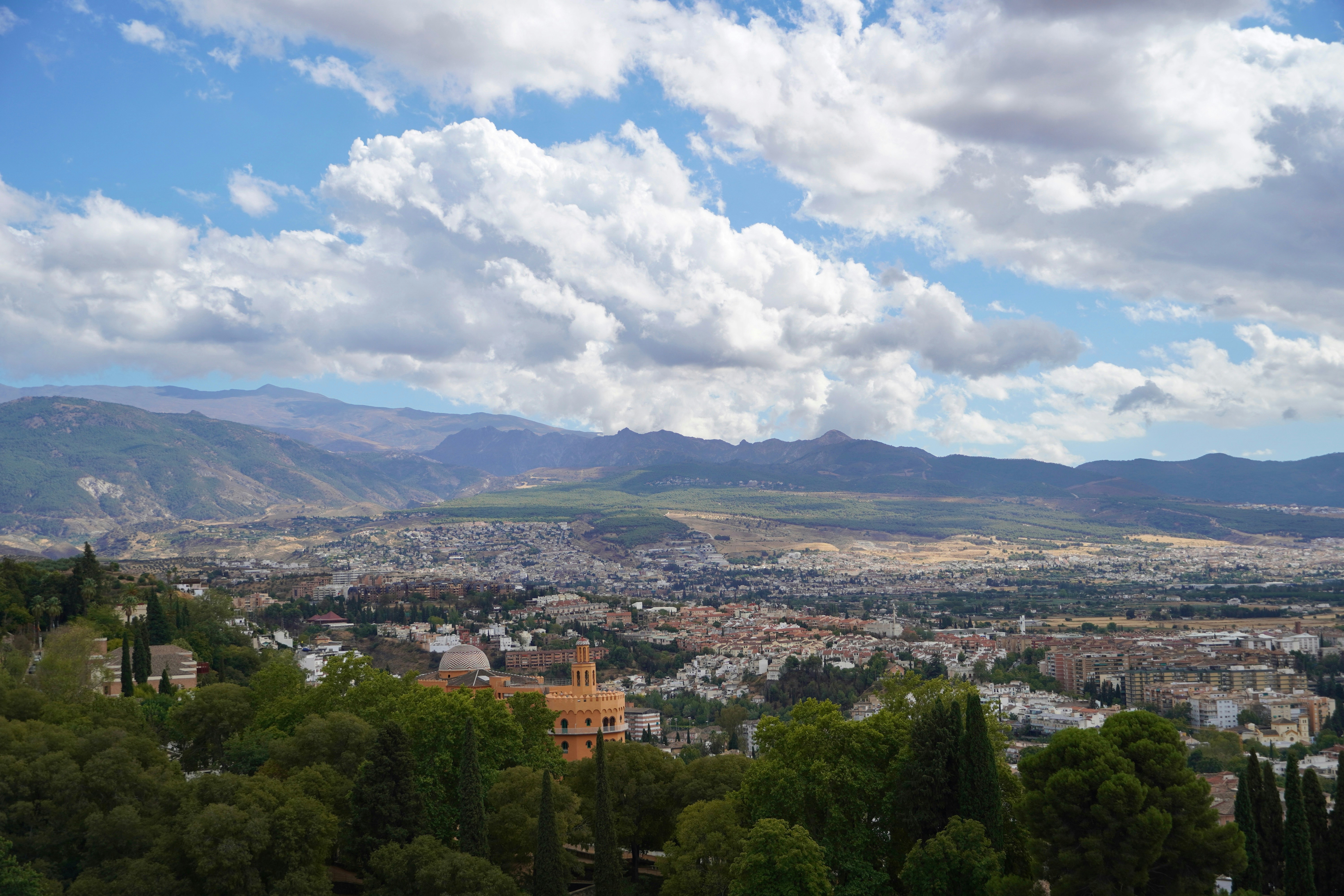 Cityscape nestled in a valley with mountains beyond.