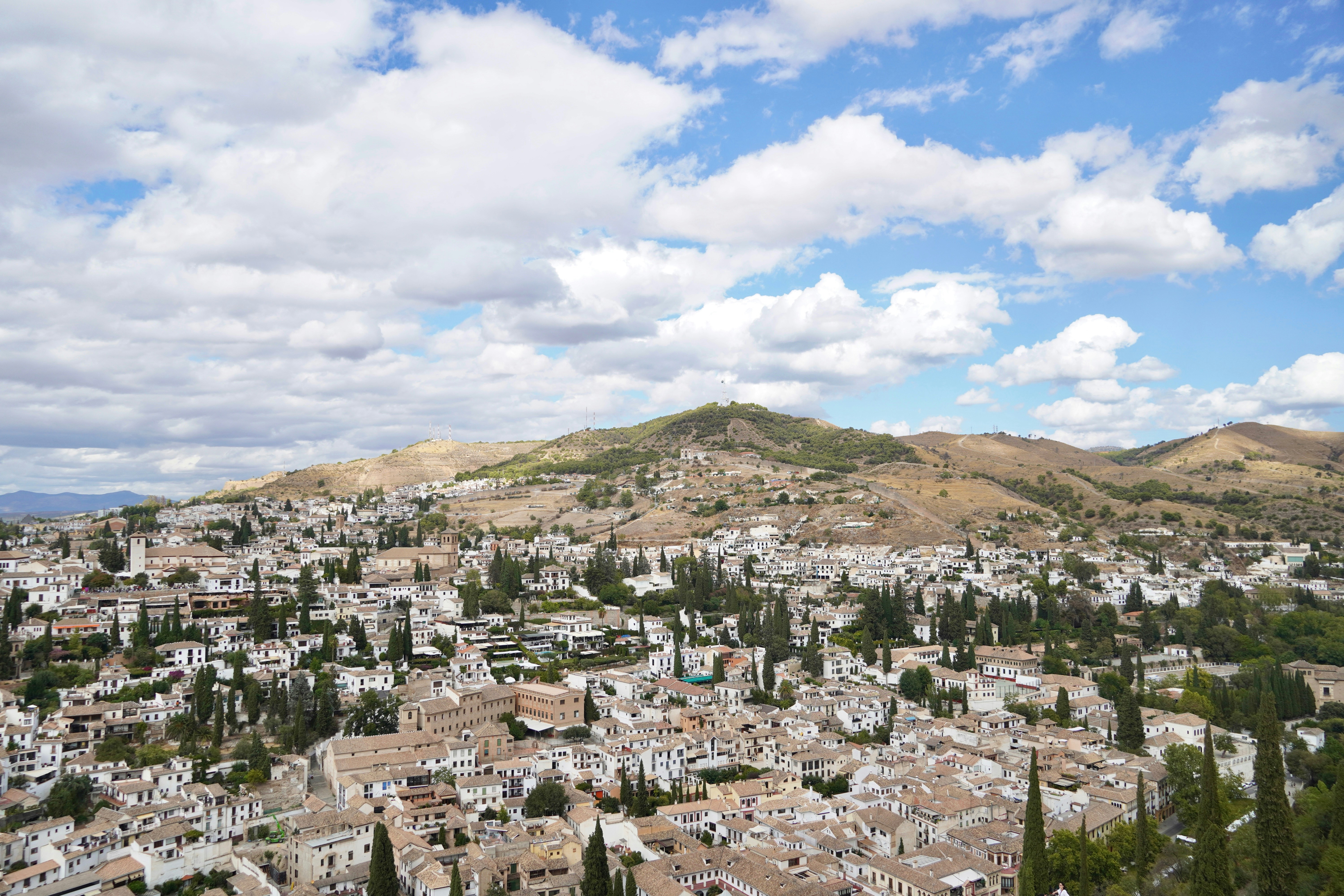 A scenic view of a white-roofed city nestled below hills.