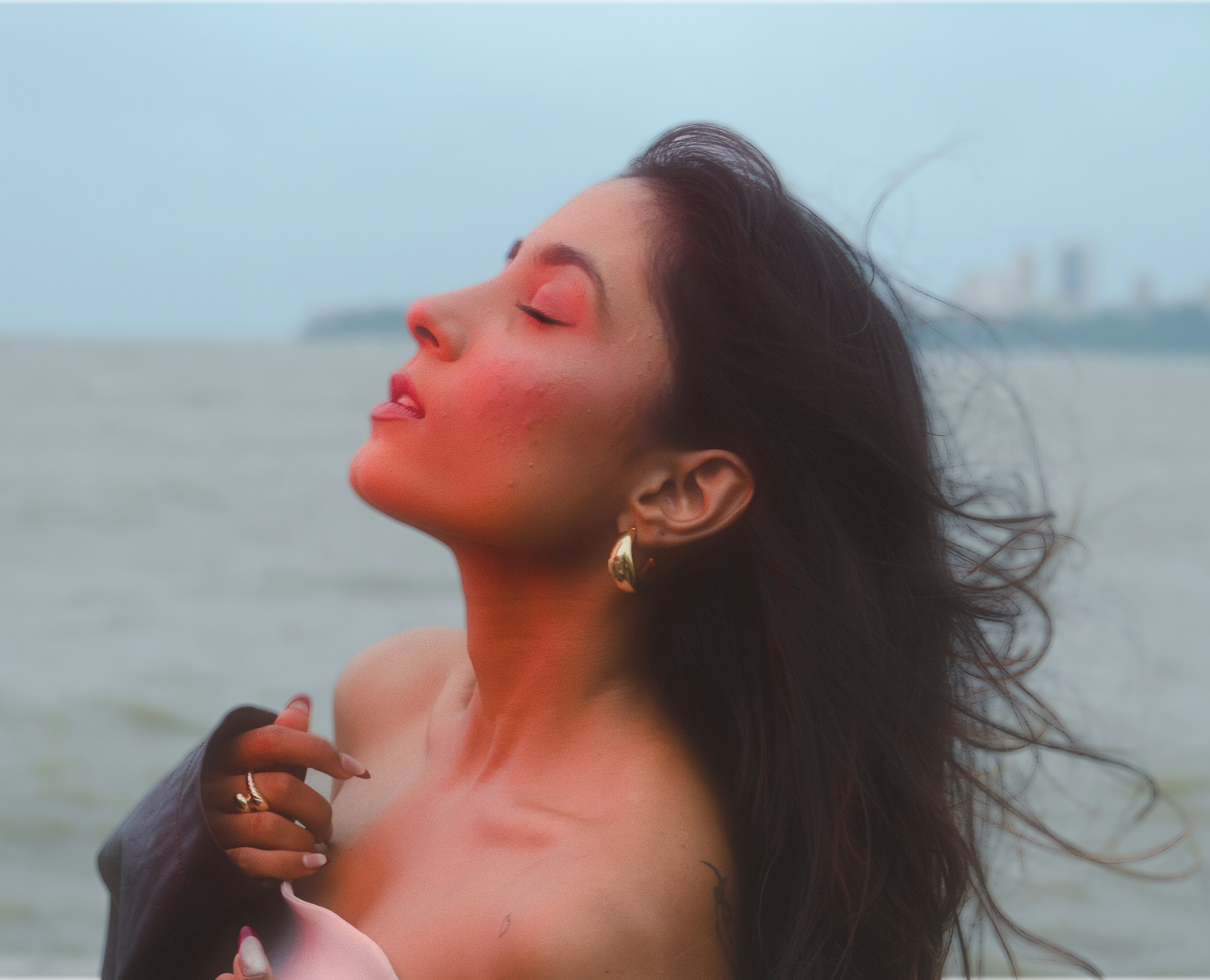 A woman with eyes closed by the ocean