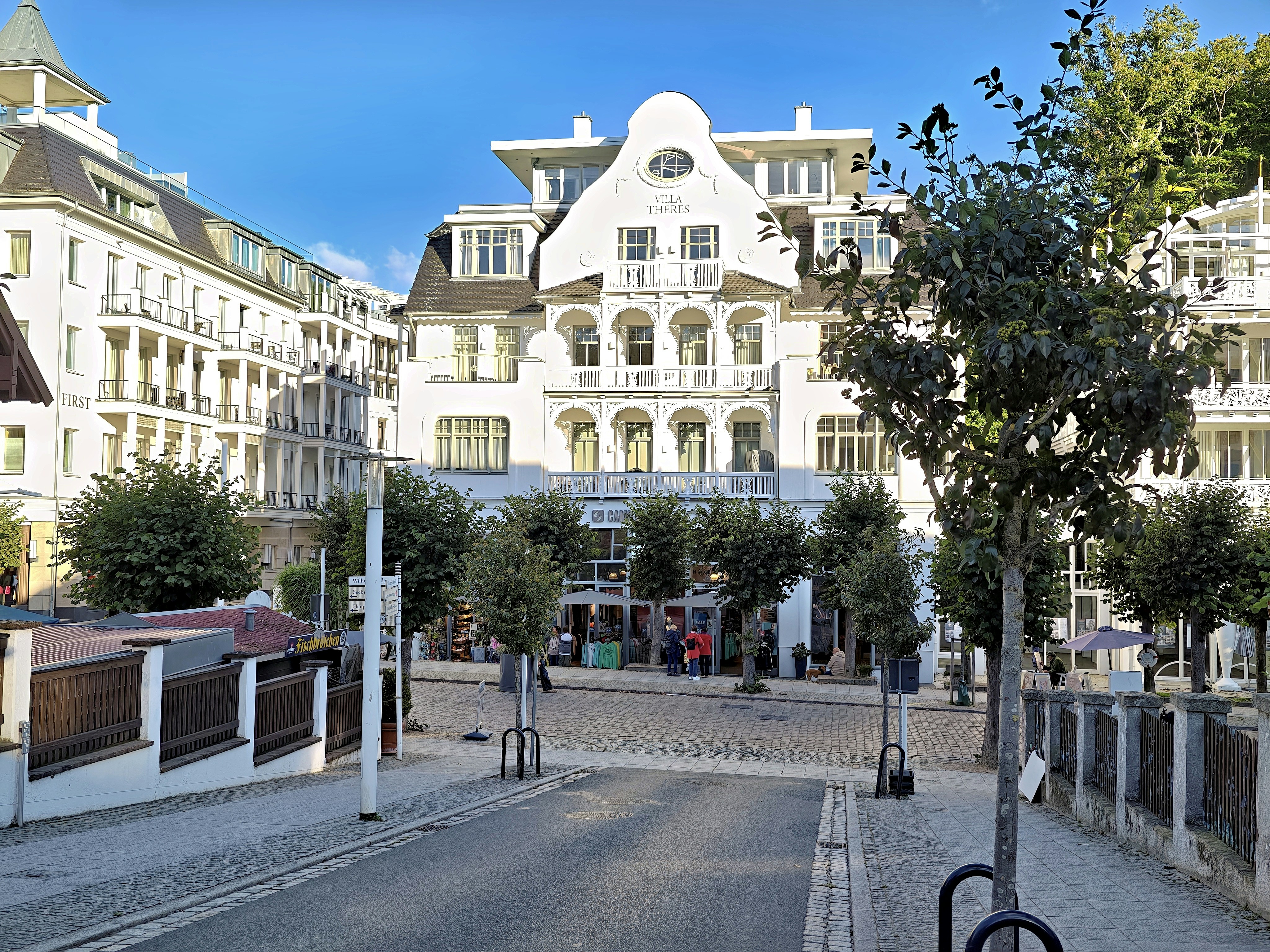 White buildings line a street with trees.