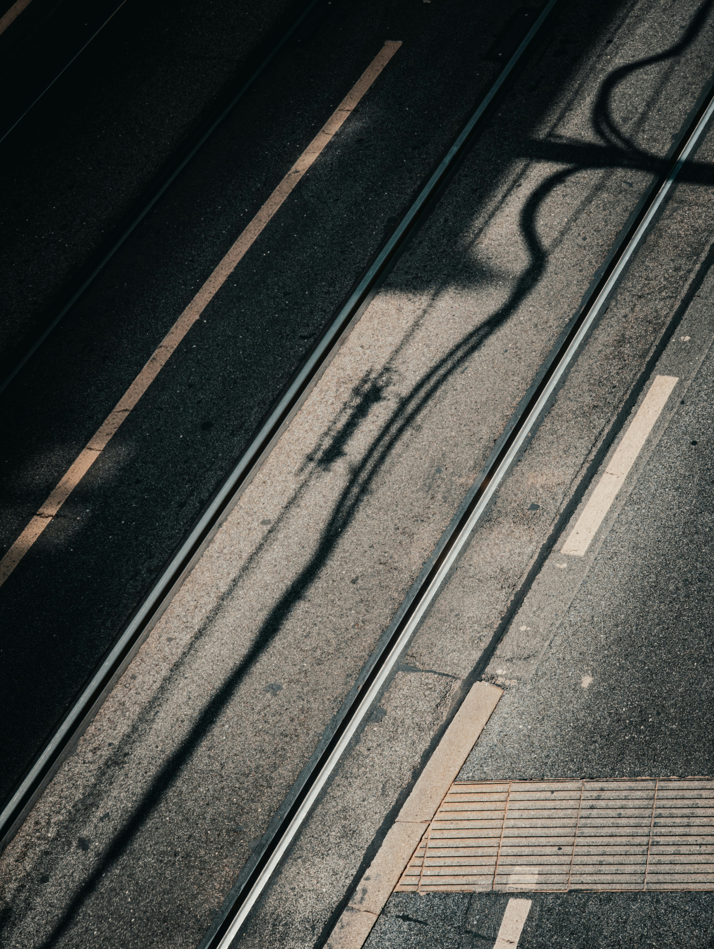 Tram tracks with a shadow of overhead wires.