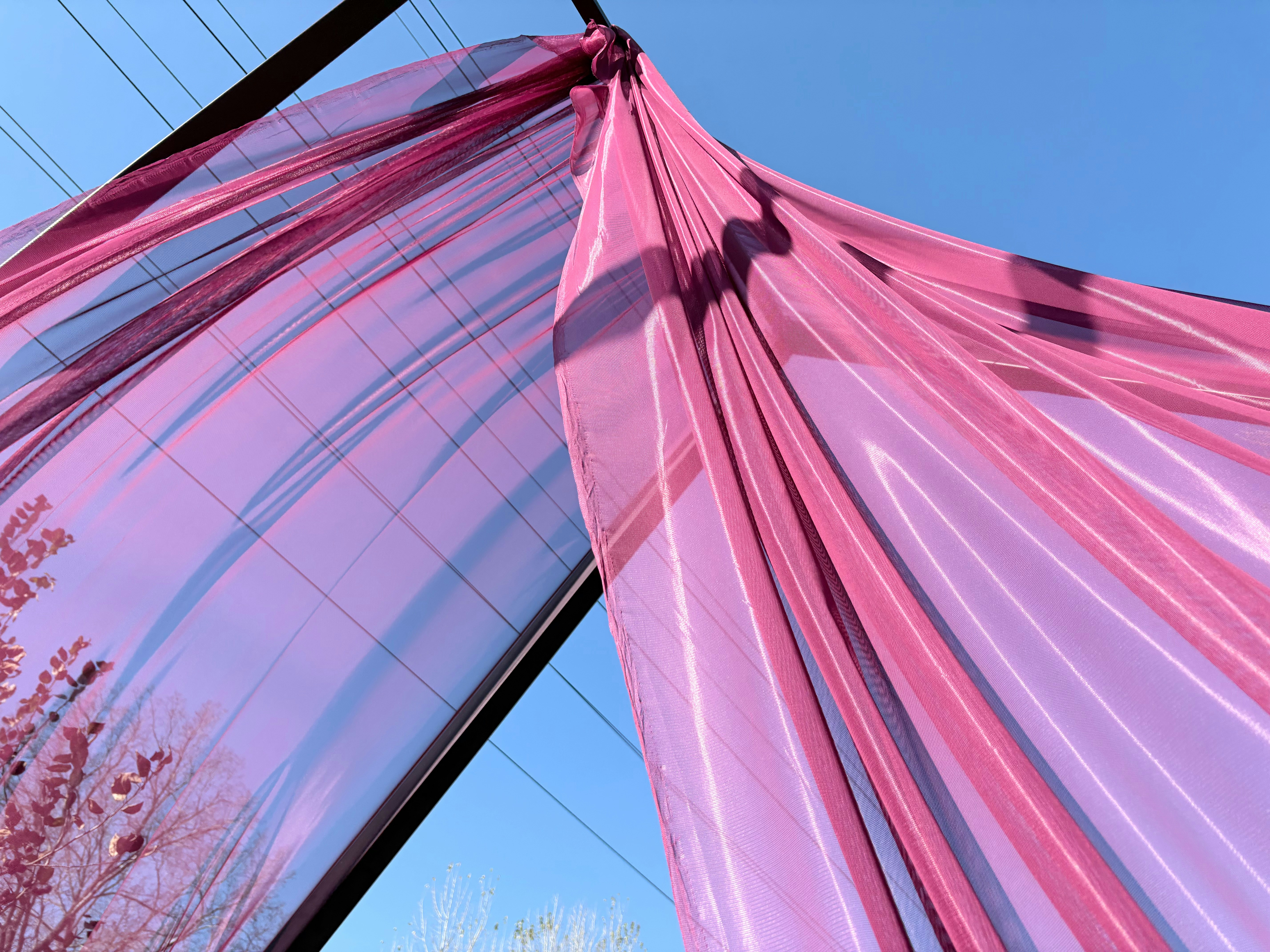 Pink fabric draped against a clear blue sky.
