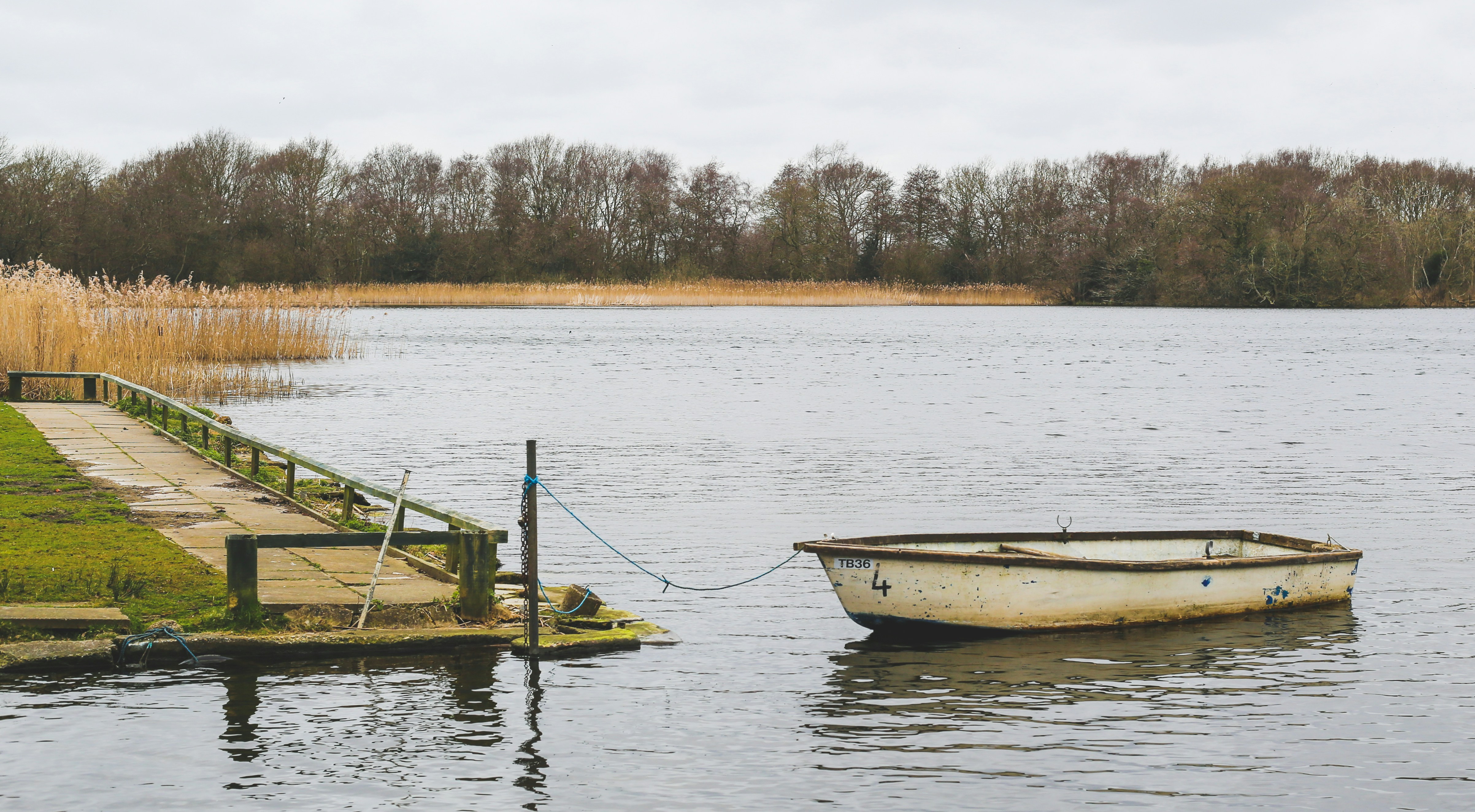 A small rowboat tied to a dock on a lake.