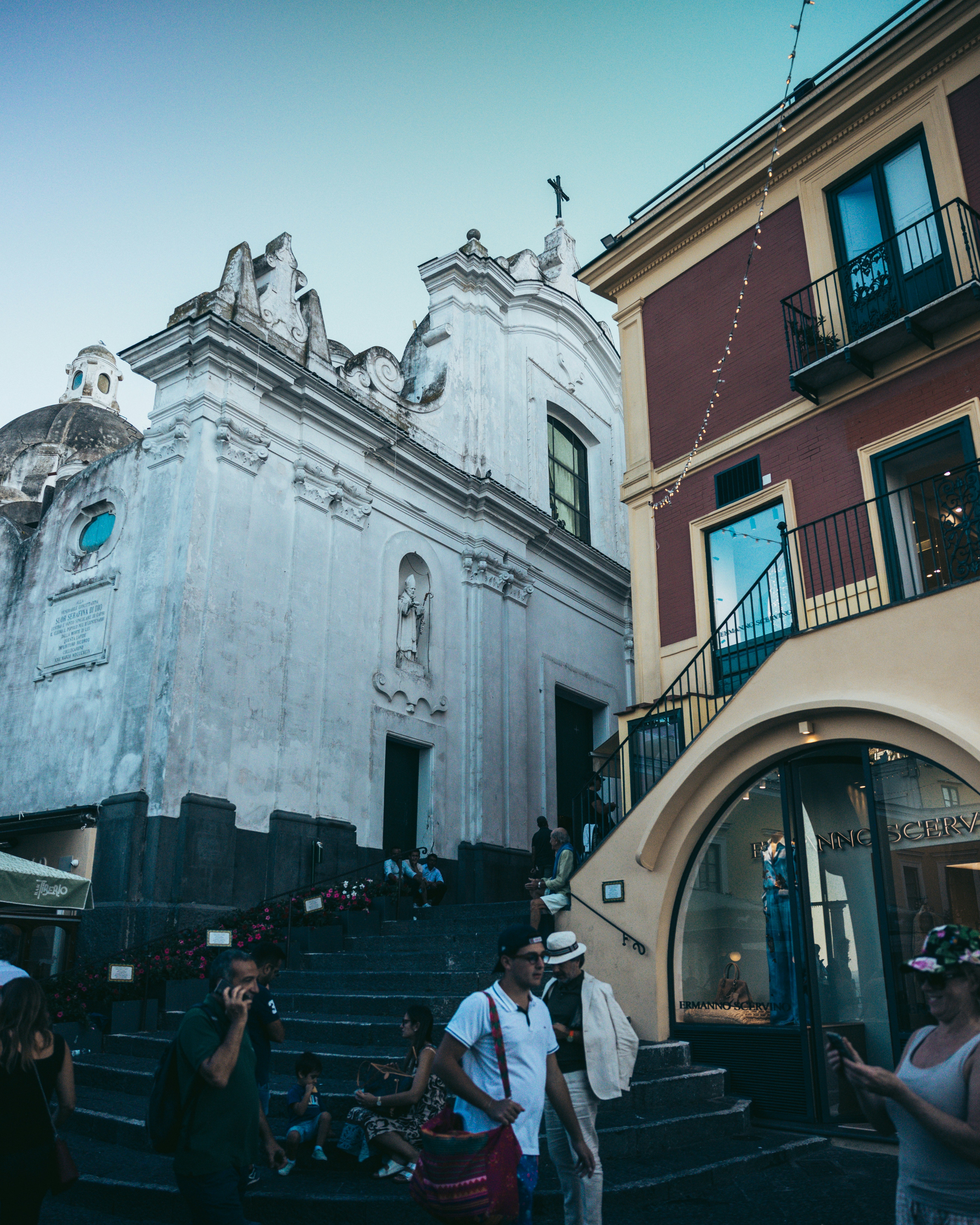 People walking up stairs towards a white church building.