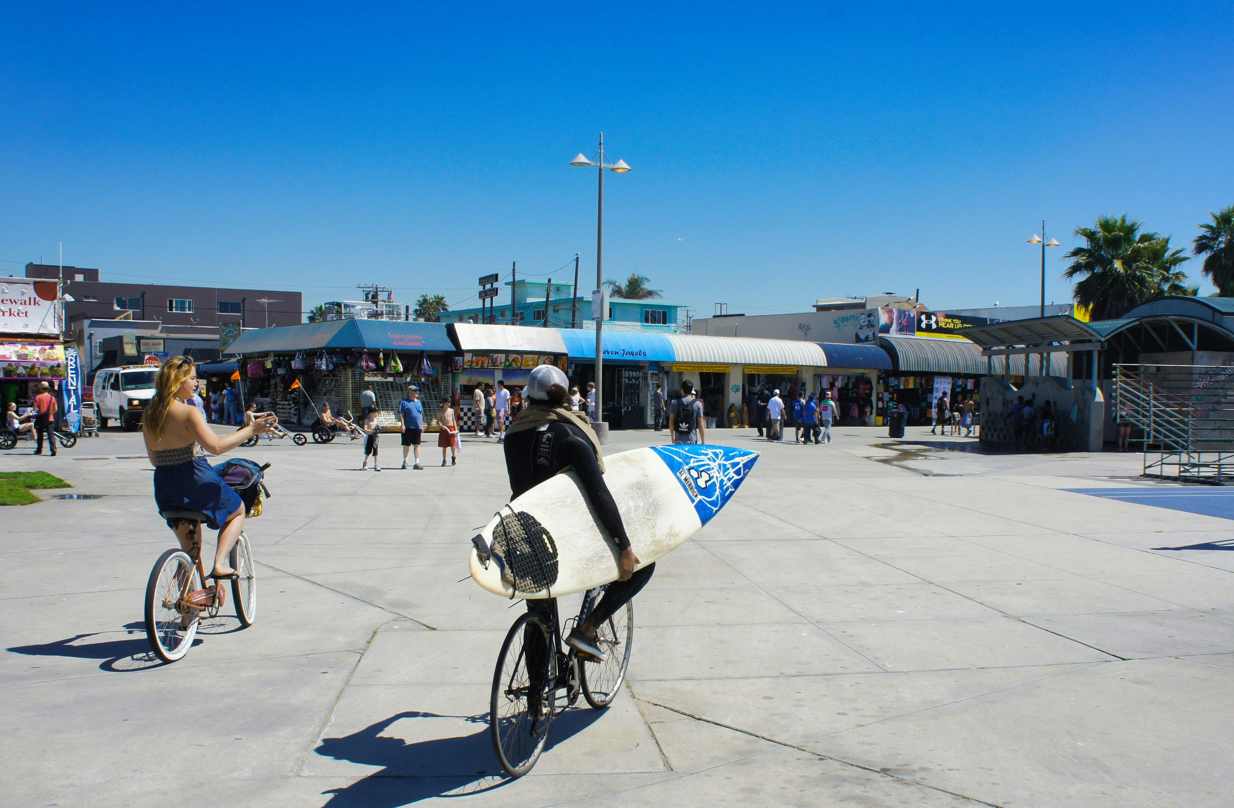 People cycling with a surfboard on a sunny day.