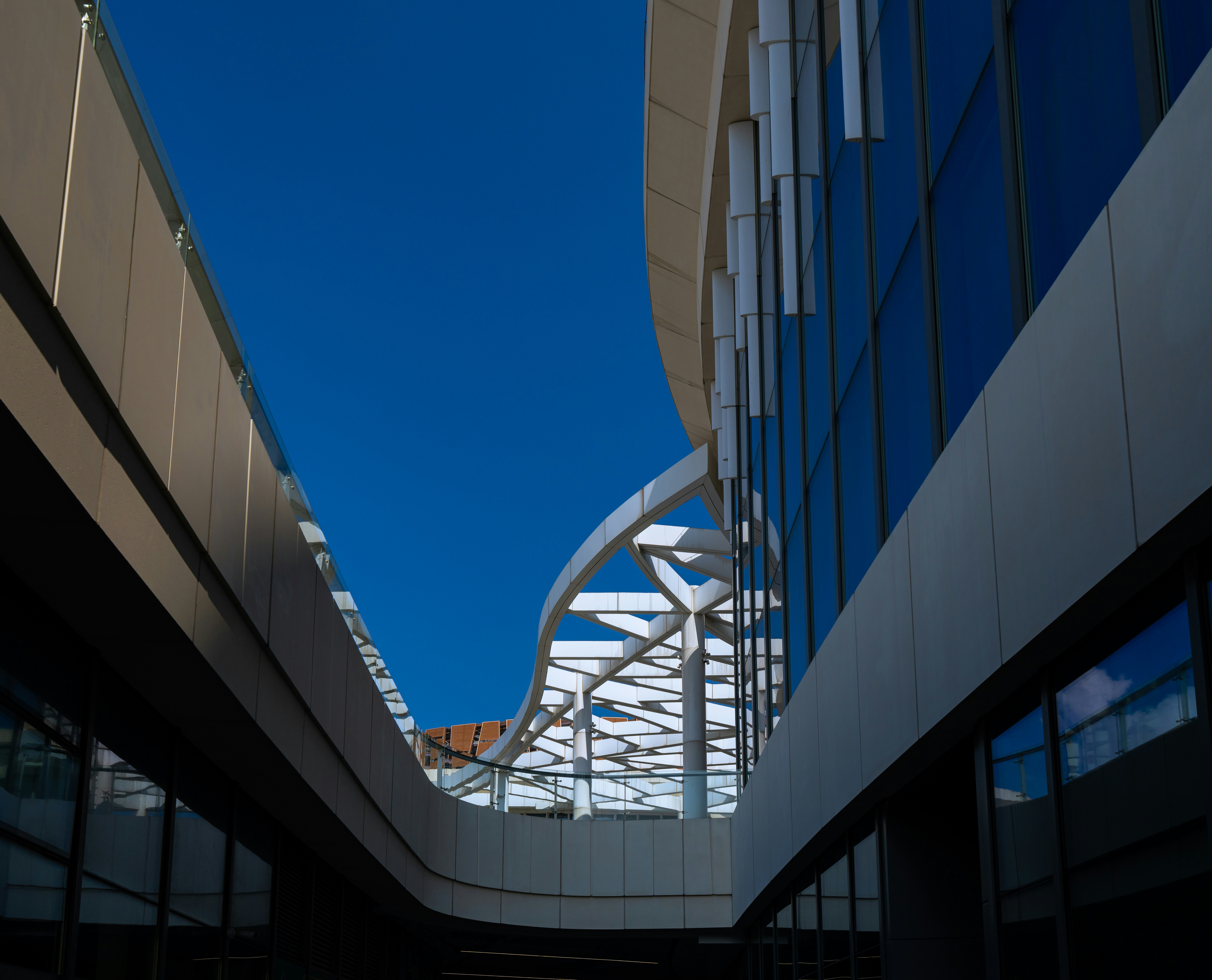 Modern architectural design featuring sleek lines and a bright blue sky, highlighting the interplay of light and shadow in an urban setting.