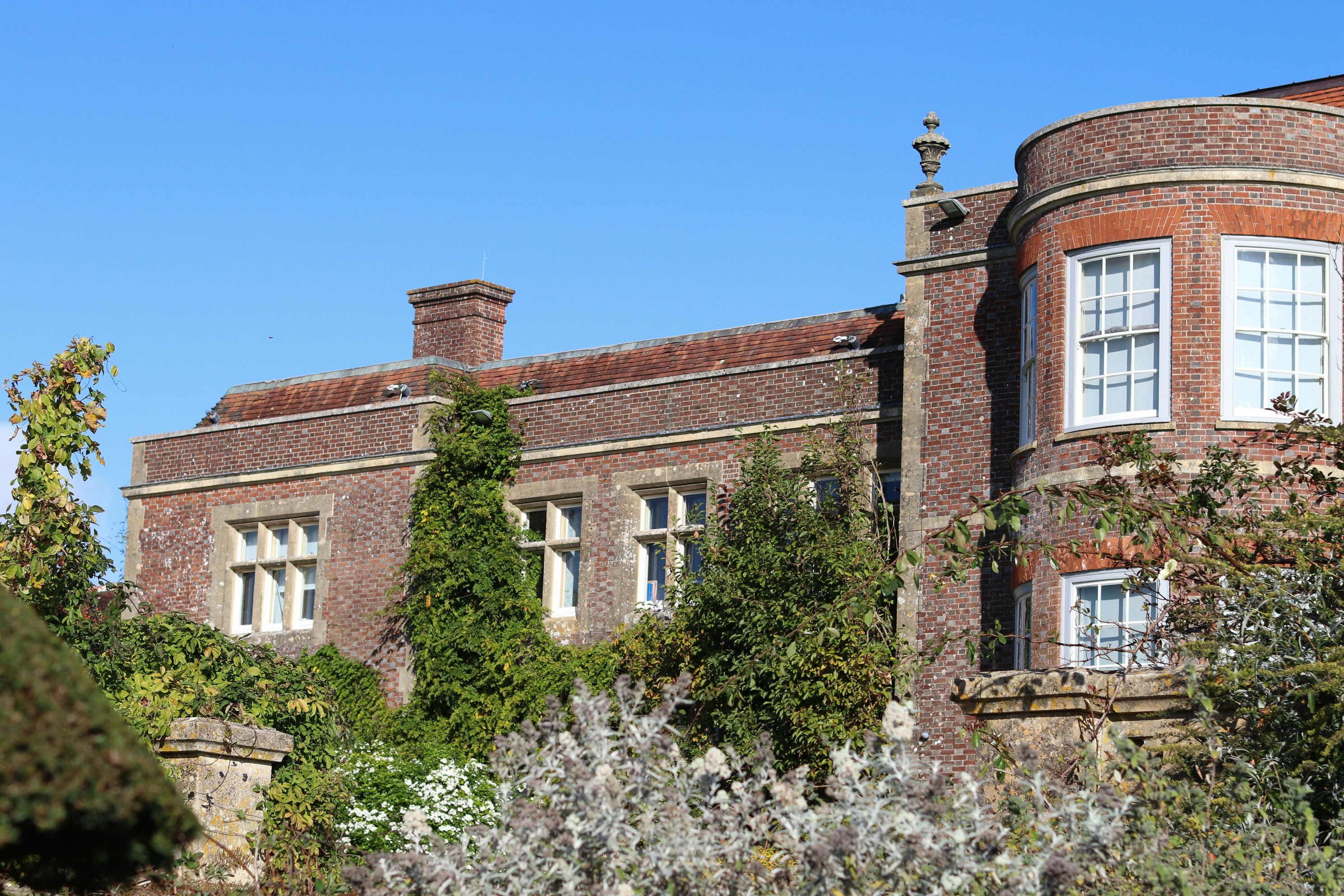 Historic brick building with lush green gardens