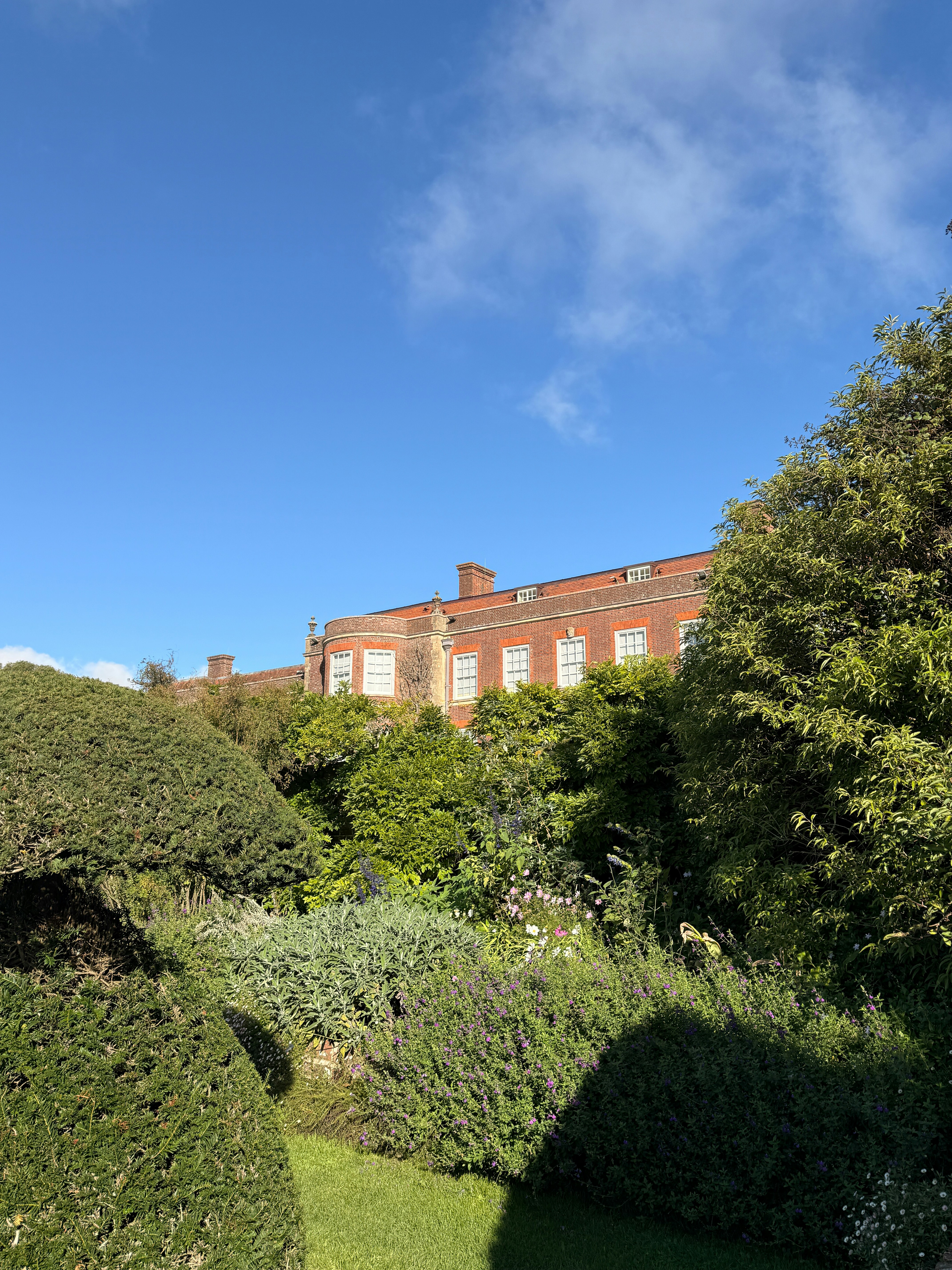 Sunlit Red-Brick Manor Rising Behind a Pruned Garden