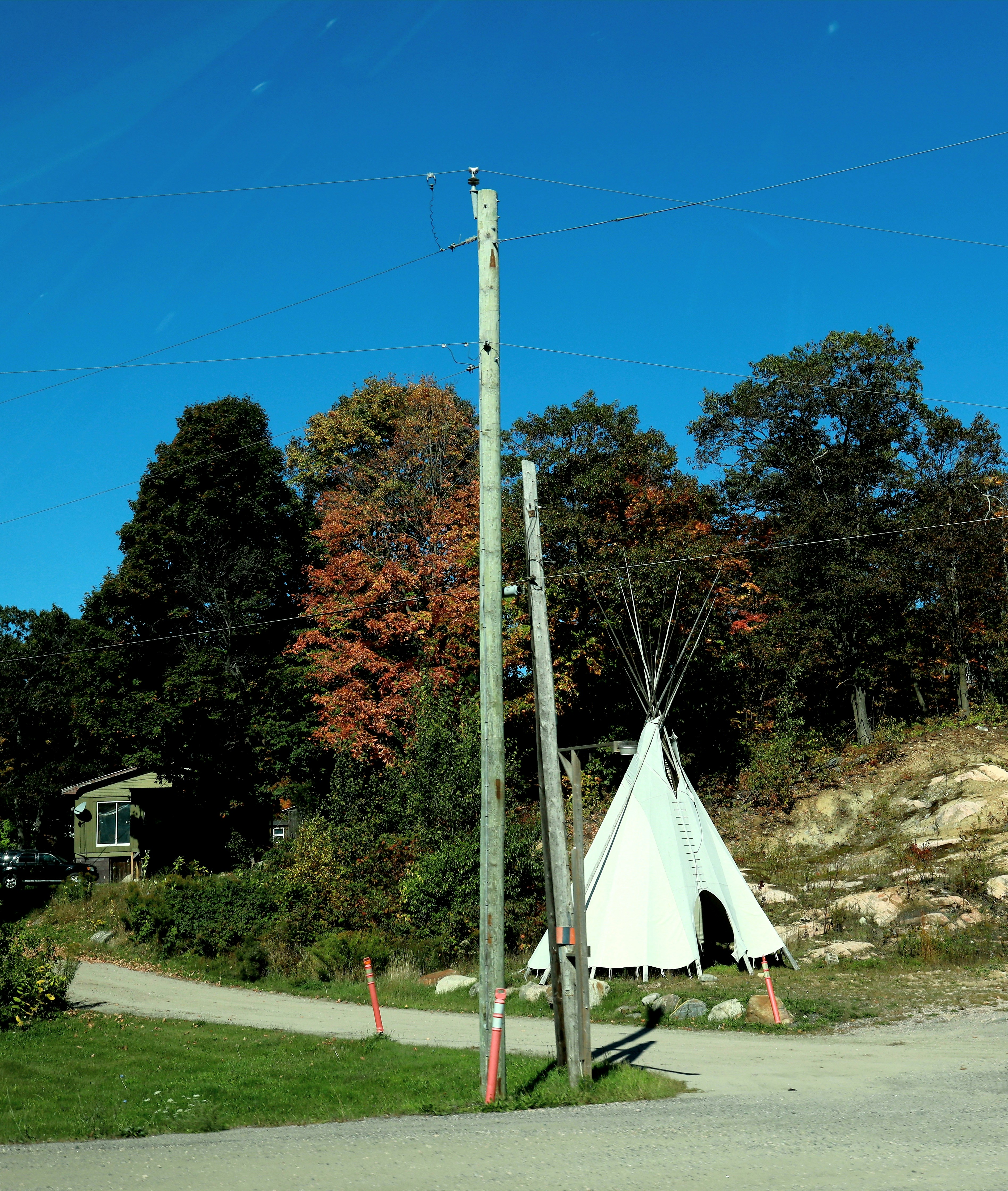White teepee stands near a small house.
