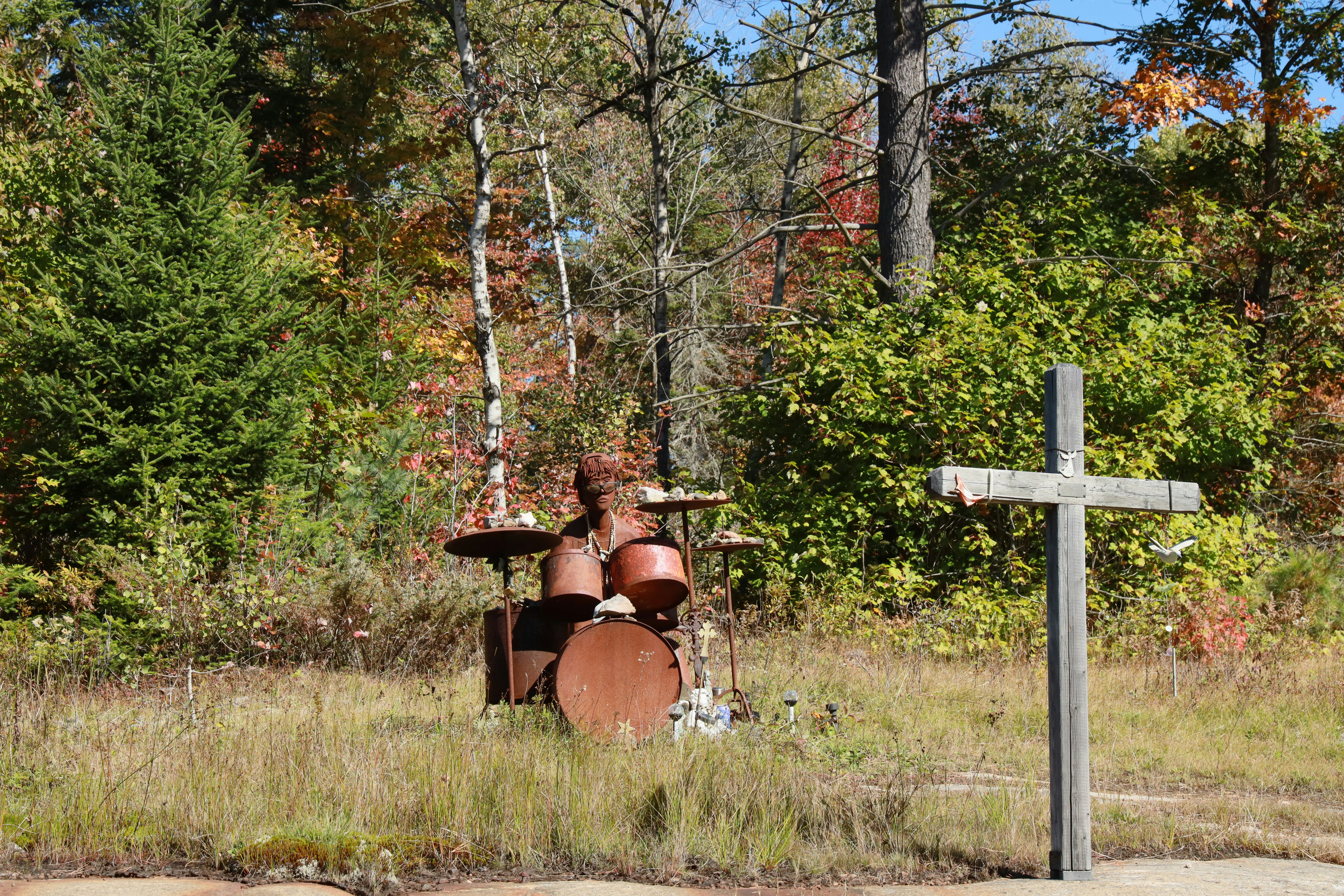 Rusty drum set and wooden cross in forest