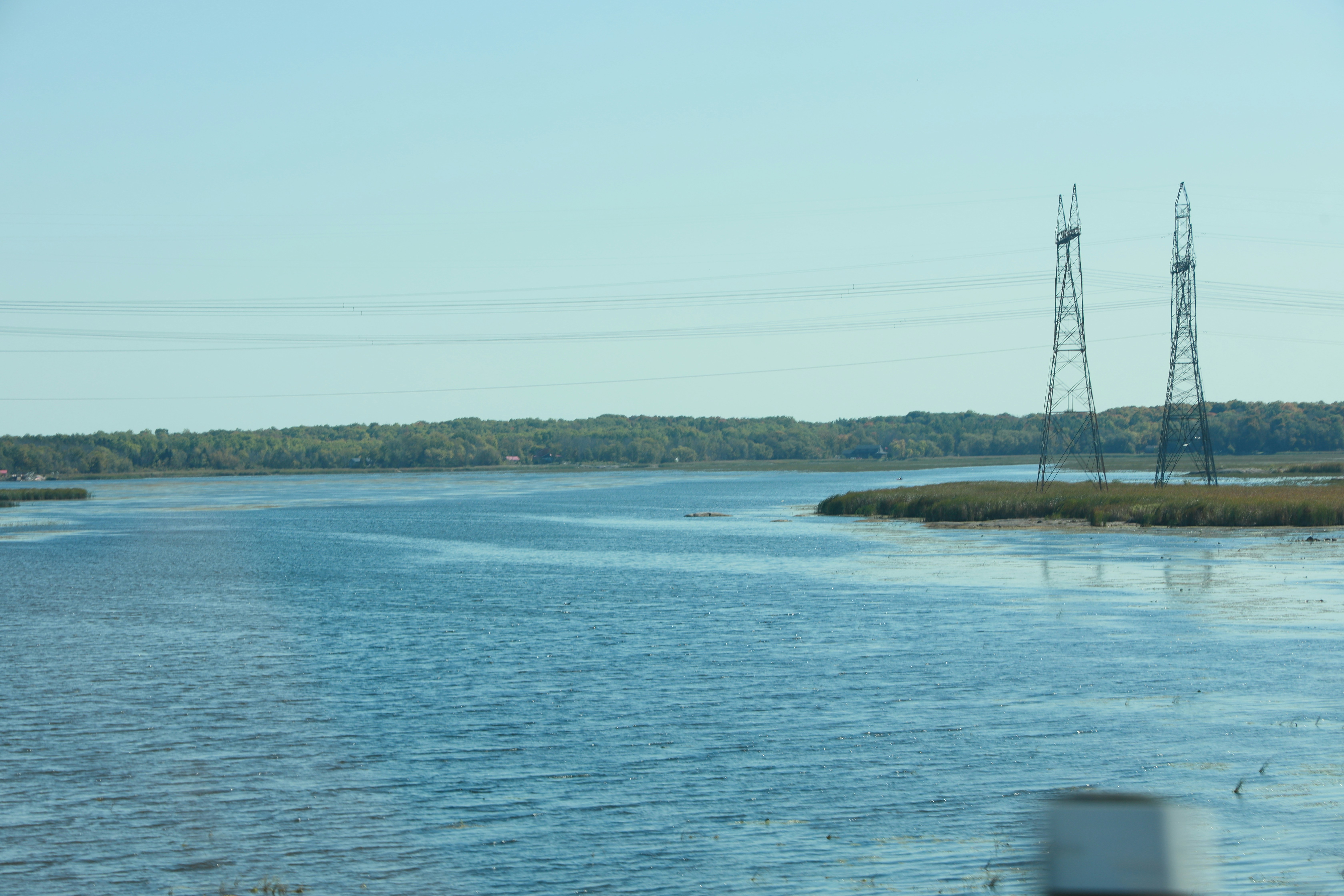 Wide river with power lines and trees on shore