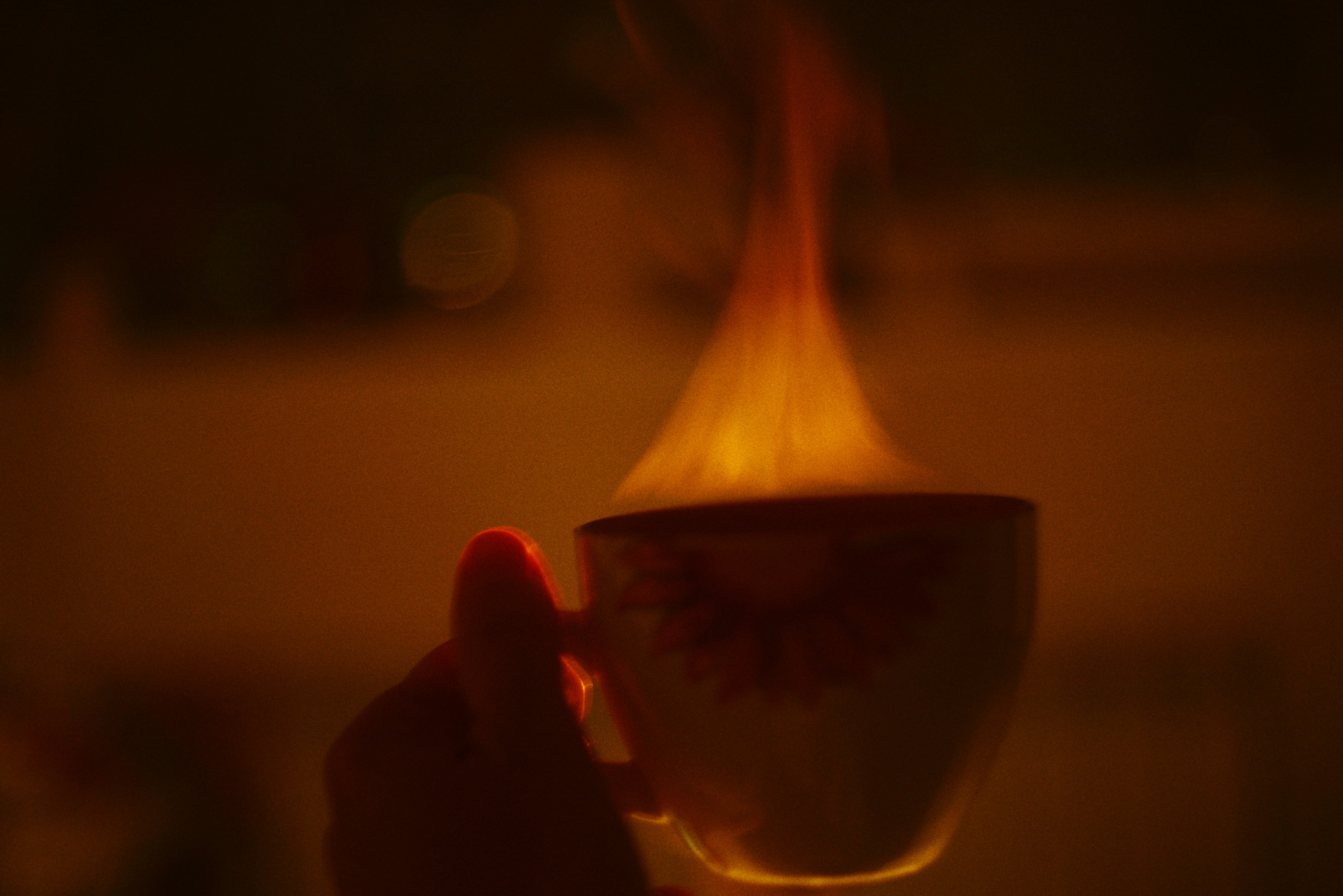 Hand holding a cup with fire rising from it