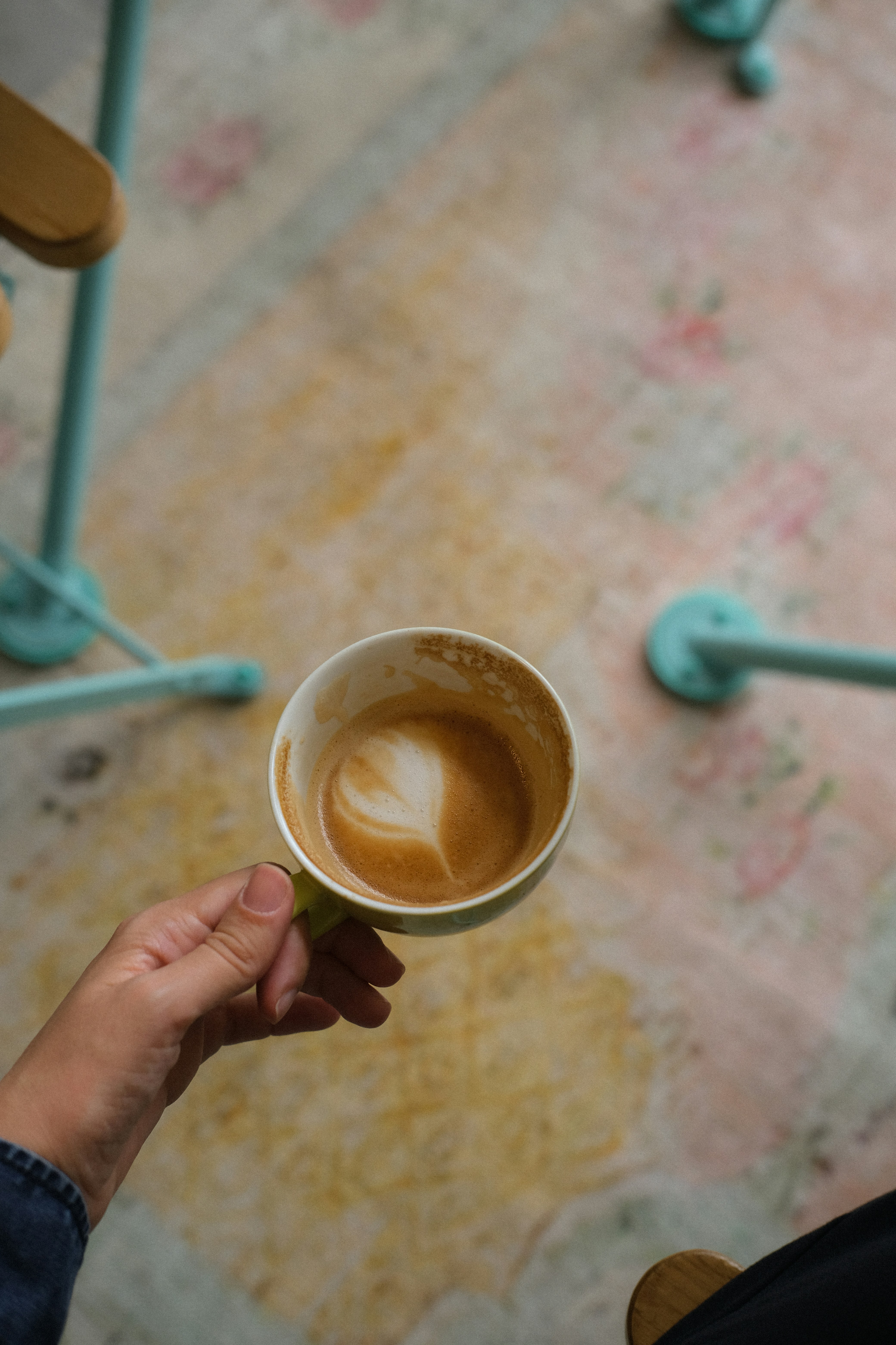 Person holding a cup of coffee with latte art.
