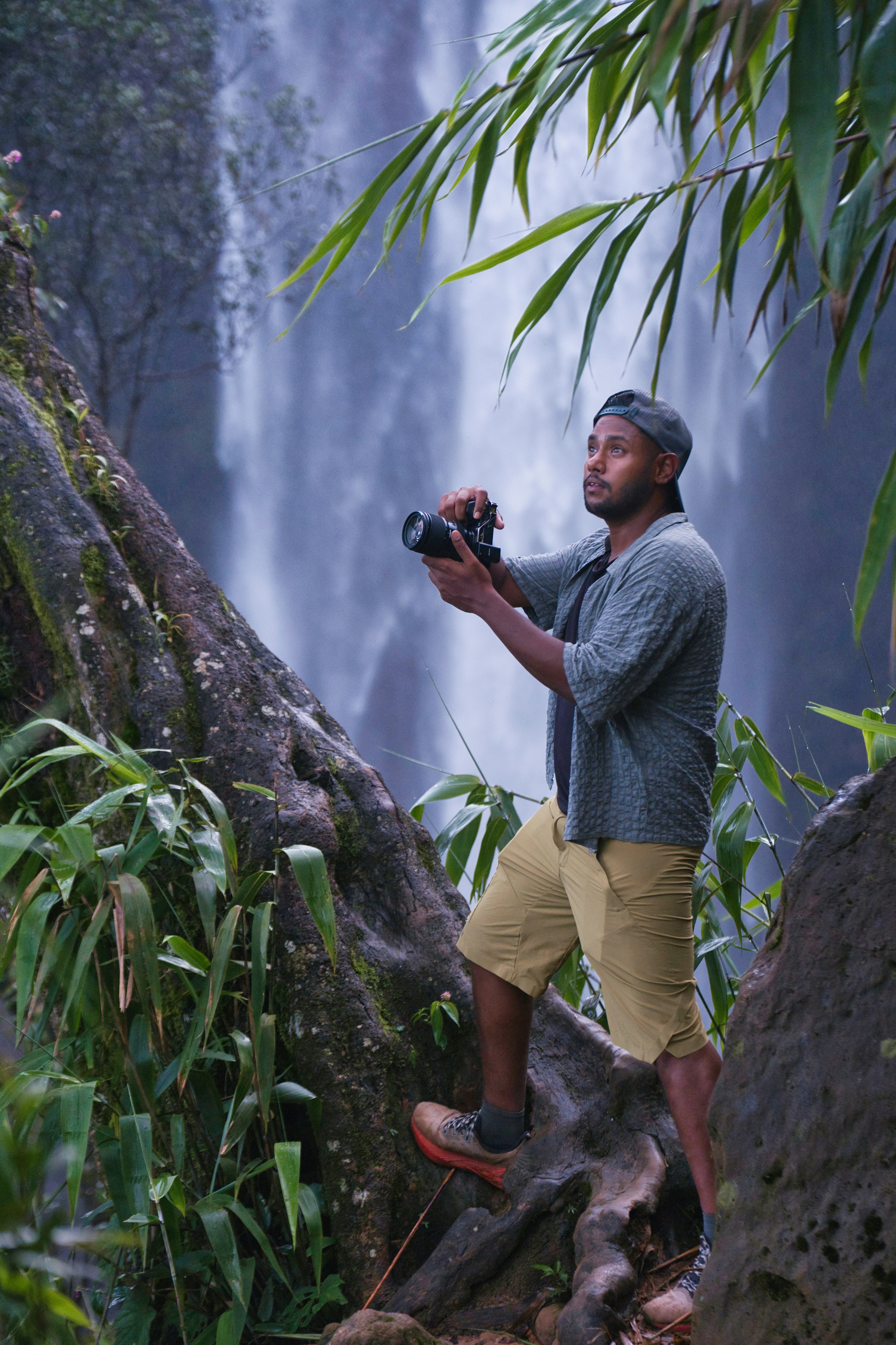 Man photographing a waterfall in a lush forest