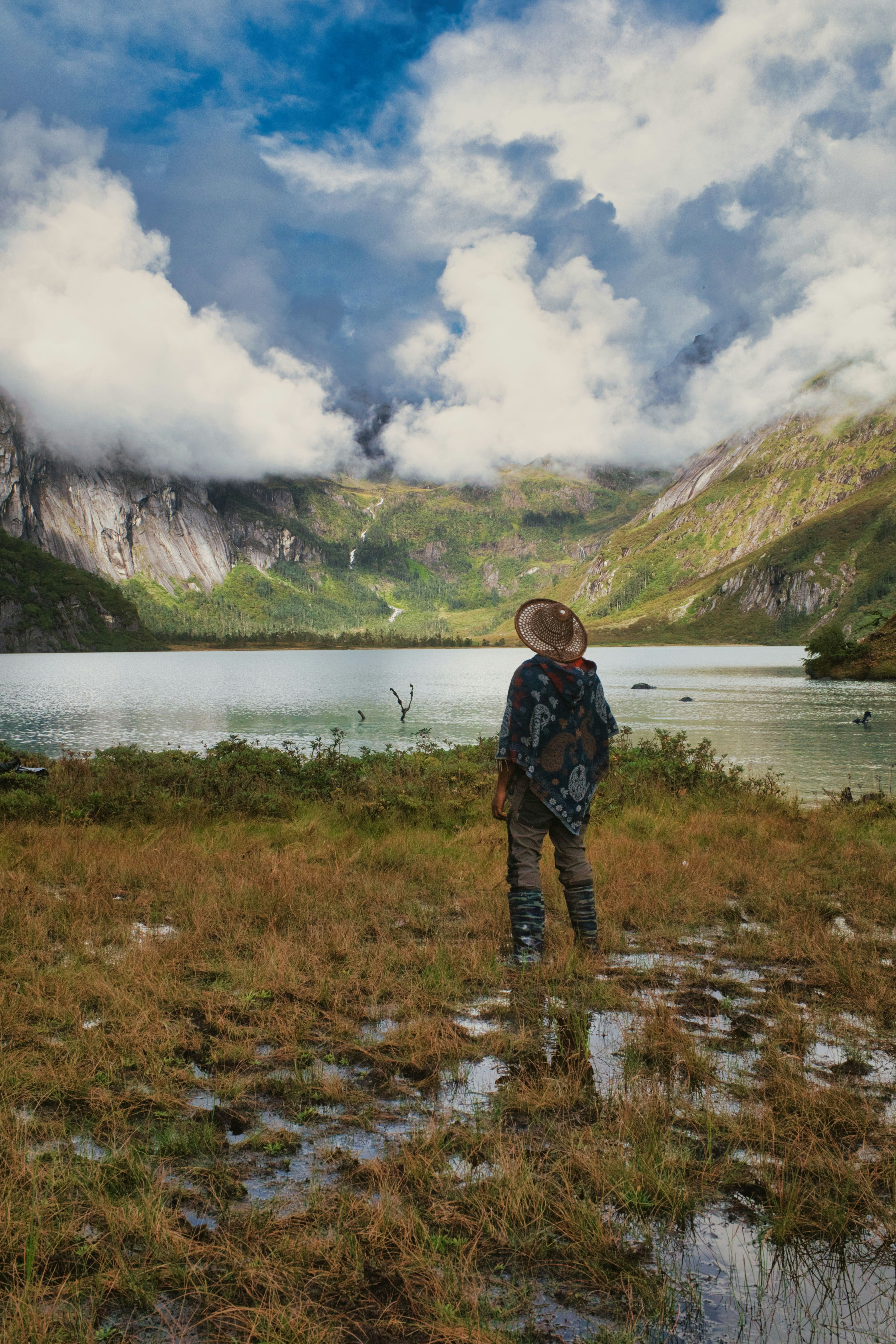Person in hat gazes at a misty mountain lake.