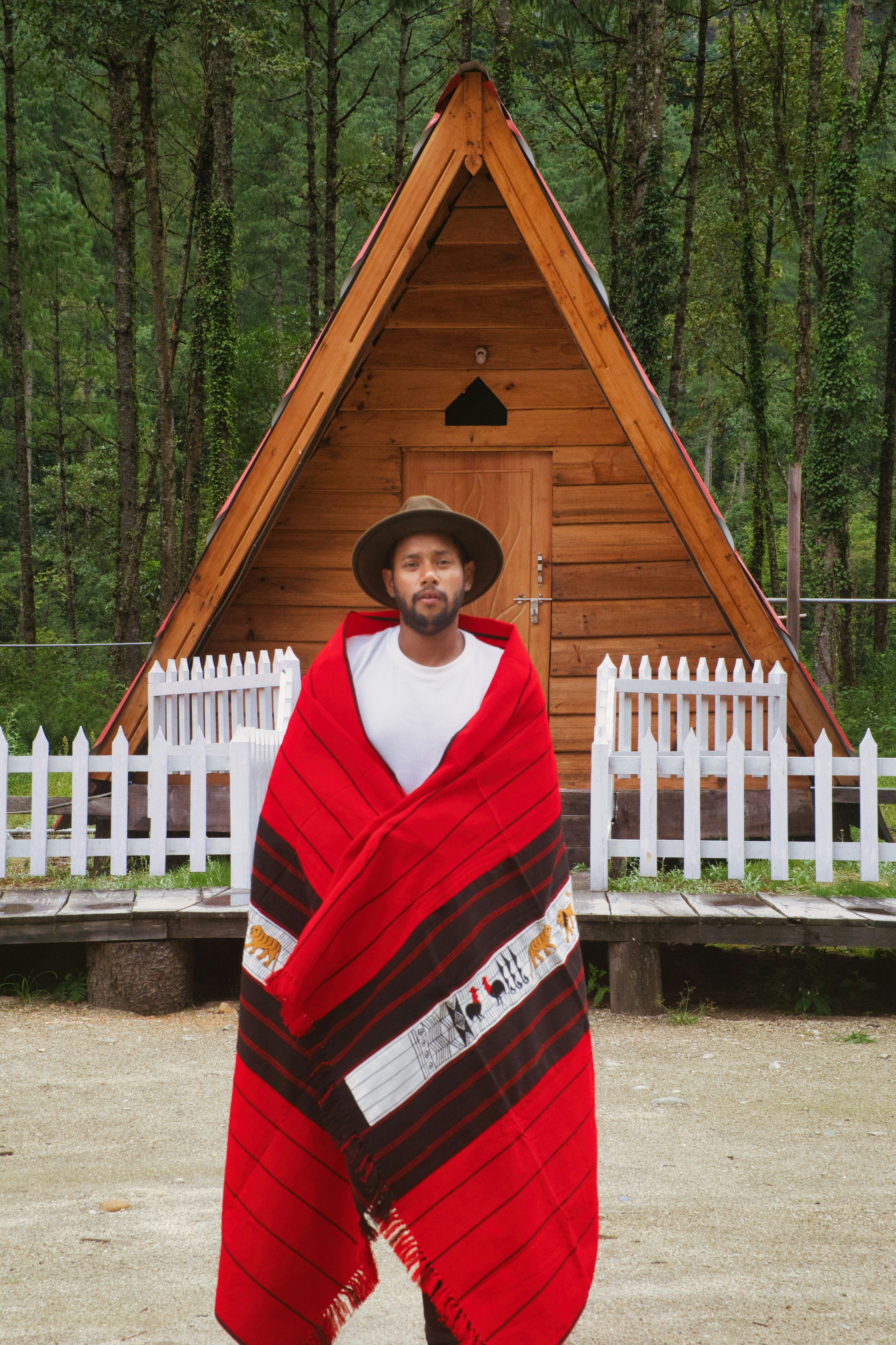 Man wrapped in blanket outside wooden cabin