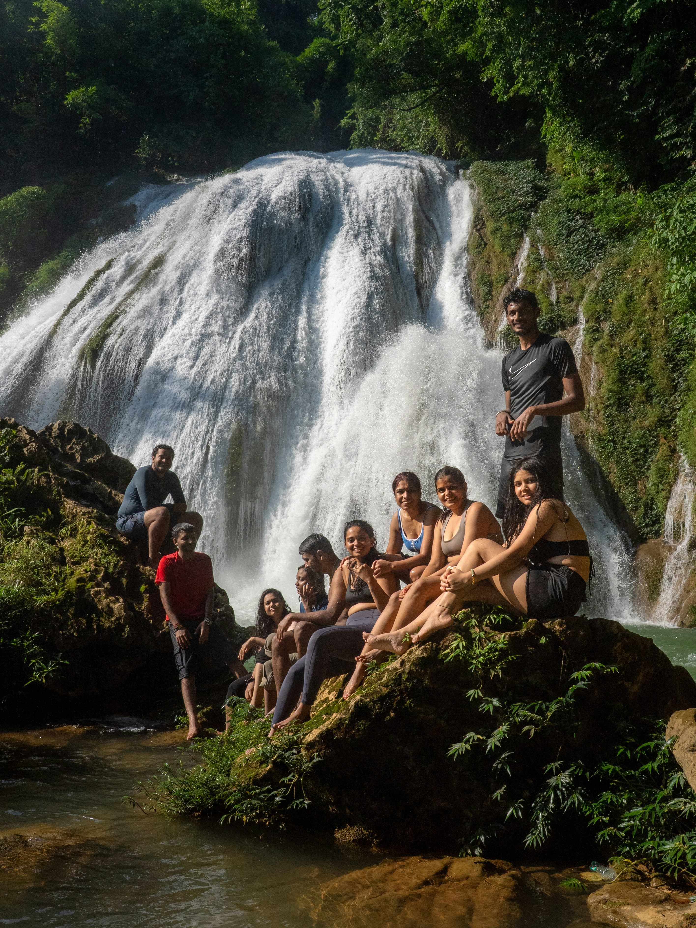 Group of people posing by a large waterfall