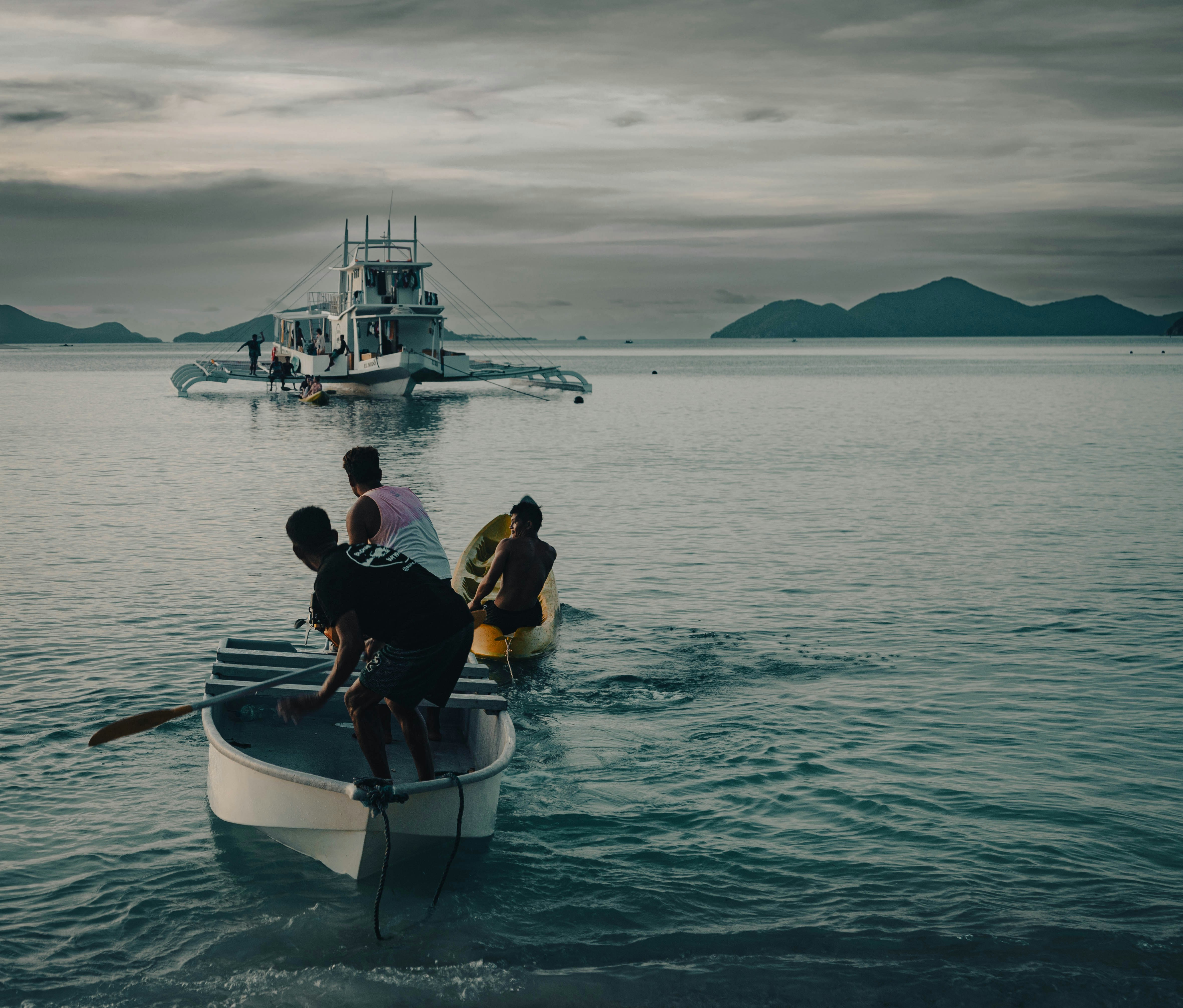 Pescadores remando en un bote pequeño hacia un bote más grande foto ...
