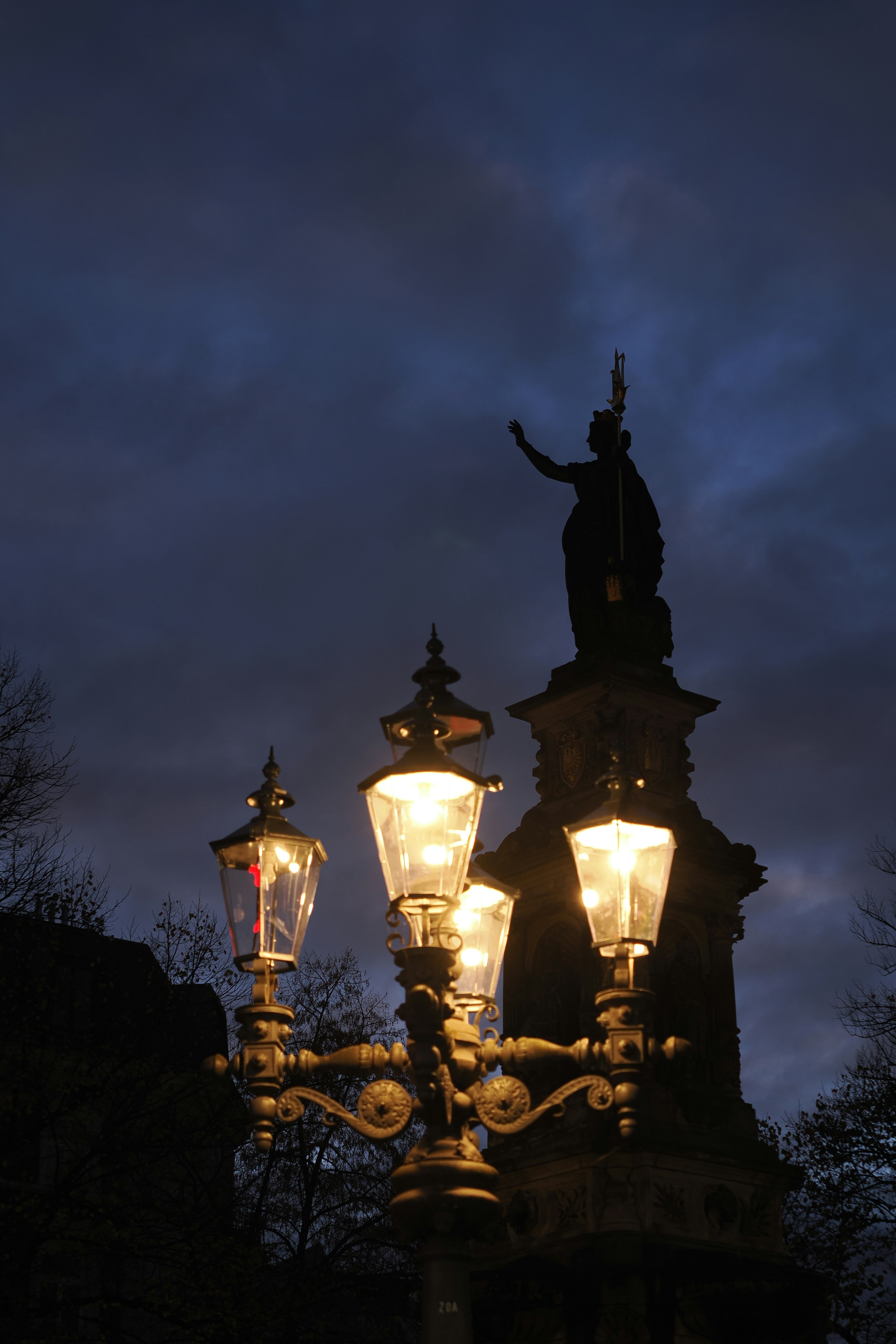 Quartet of Lanterns Crown a Monument Beneath a Moody Dusk