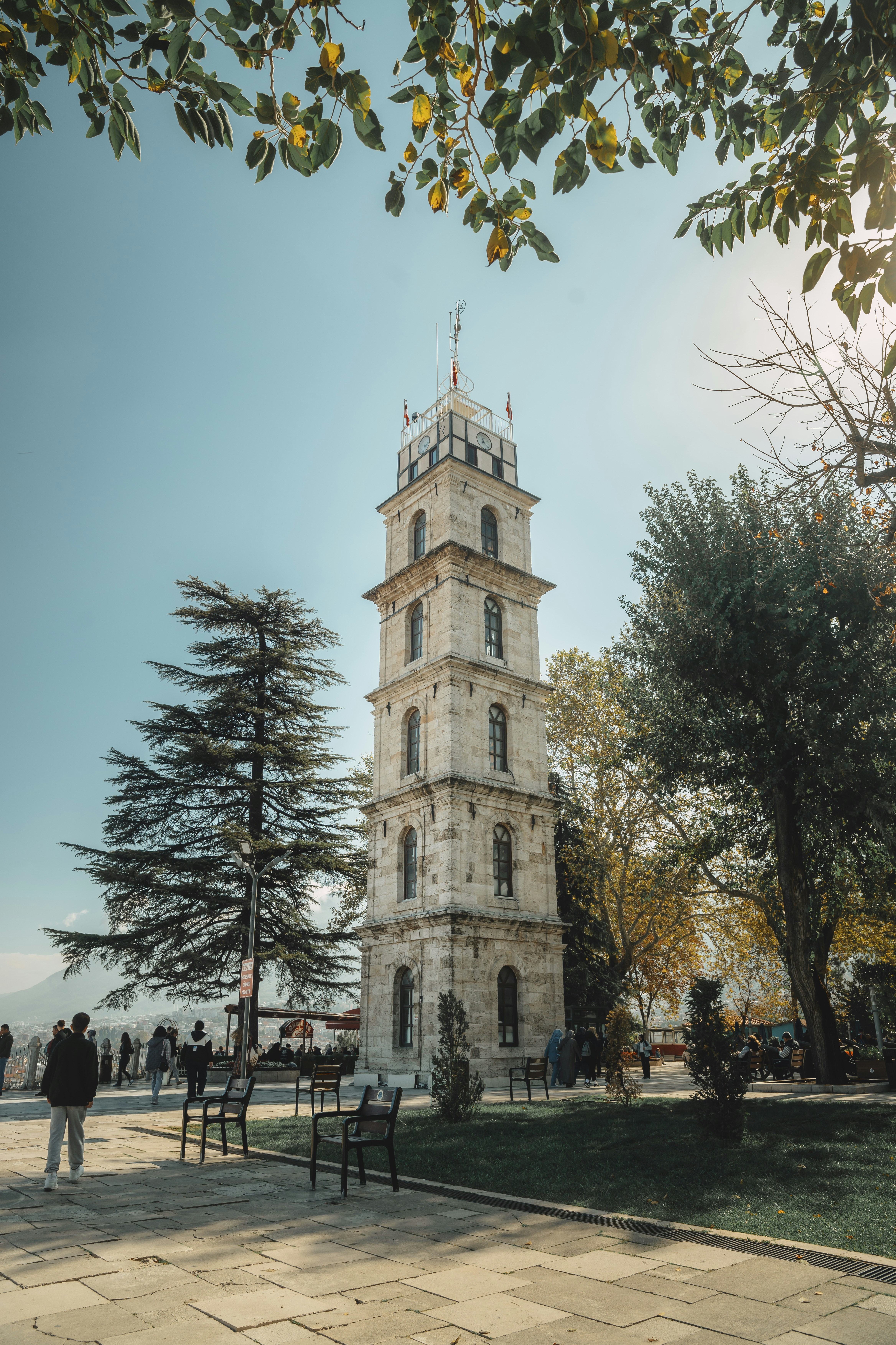 Historic tower surrounded by lush greenery and visitors enjoying the serene park atmosphere. A blend of architectural elegance and natural beauty.