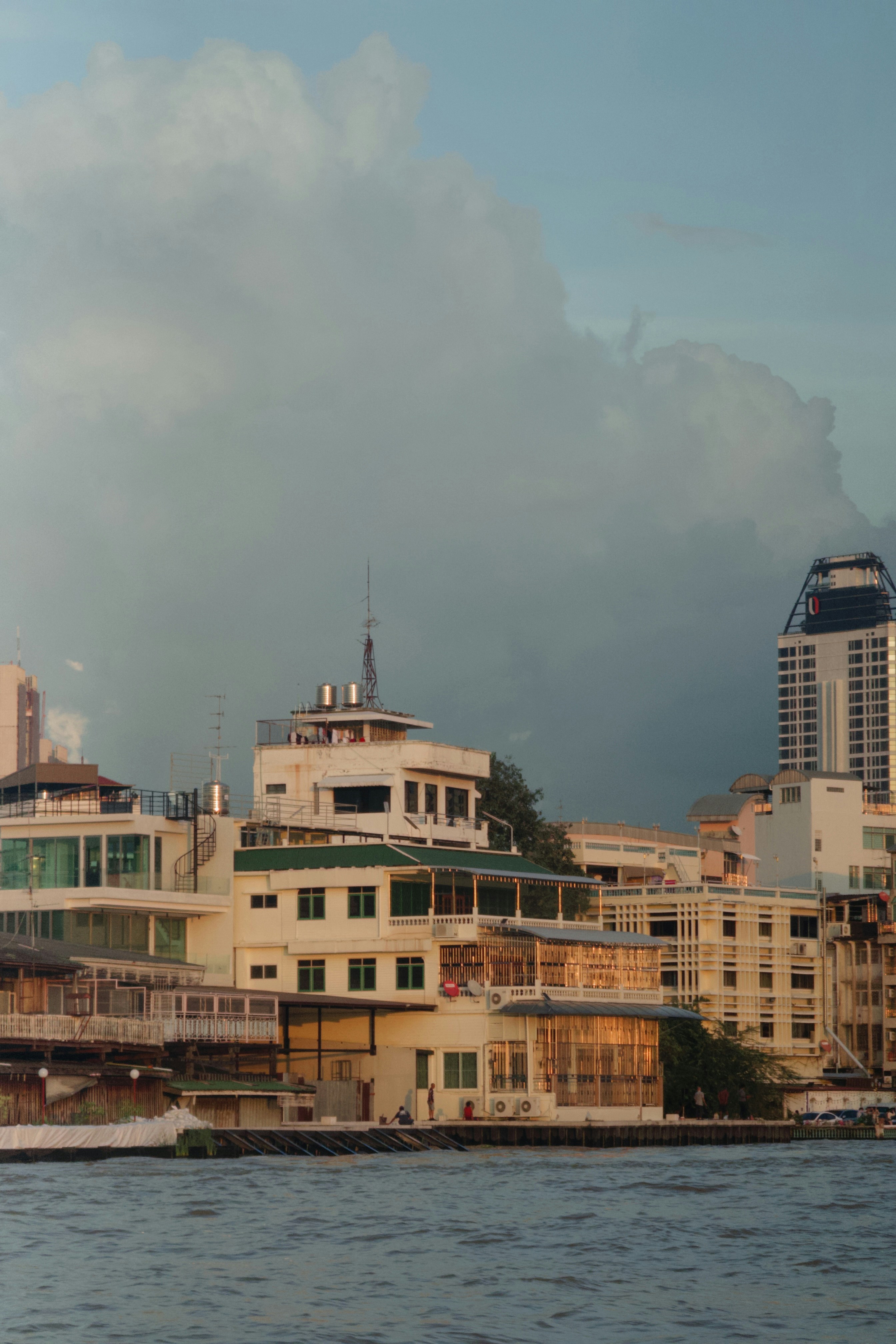 Buildings line a river under a cloudy sky.