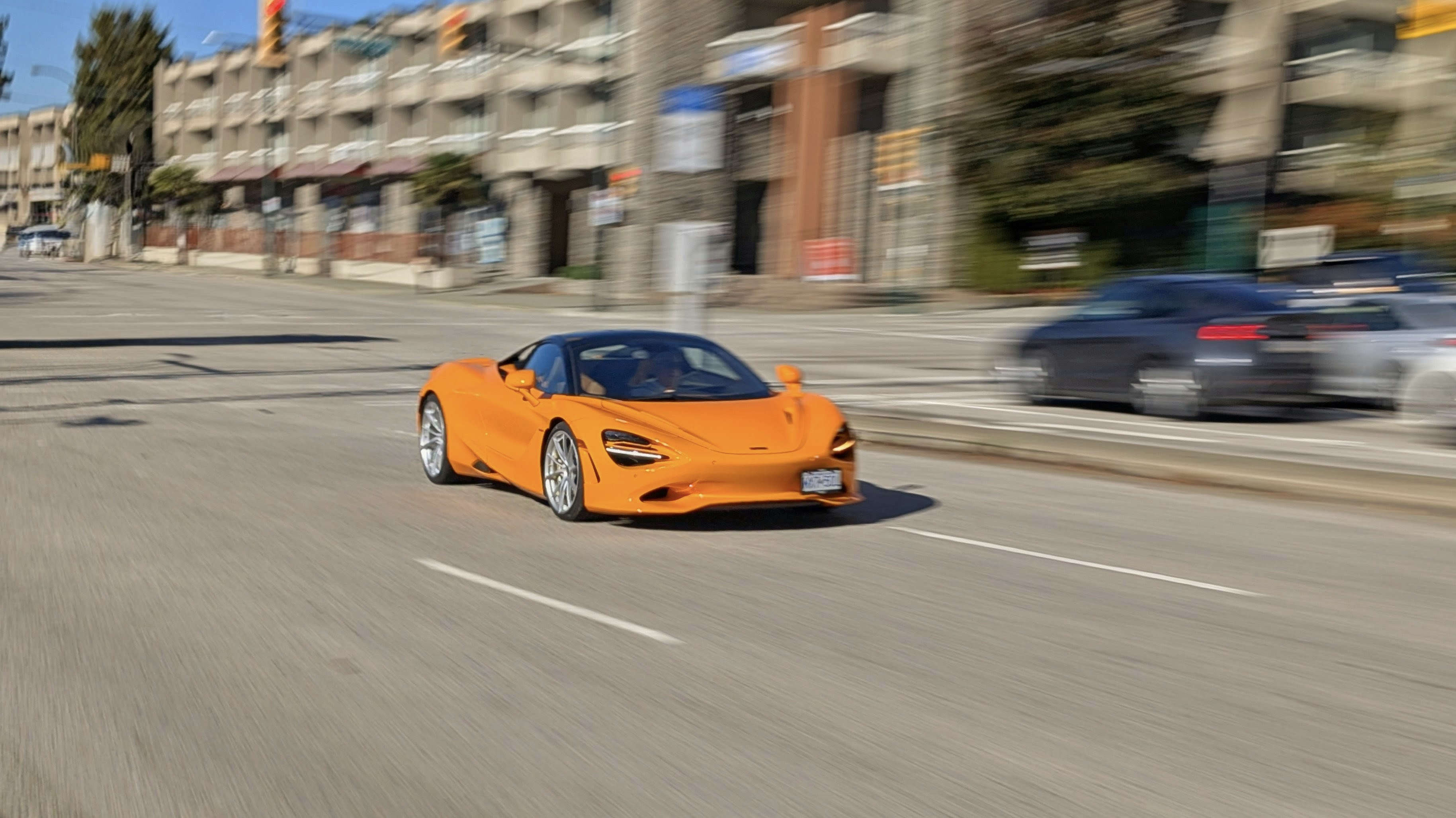 Orange sports car driving on a city street