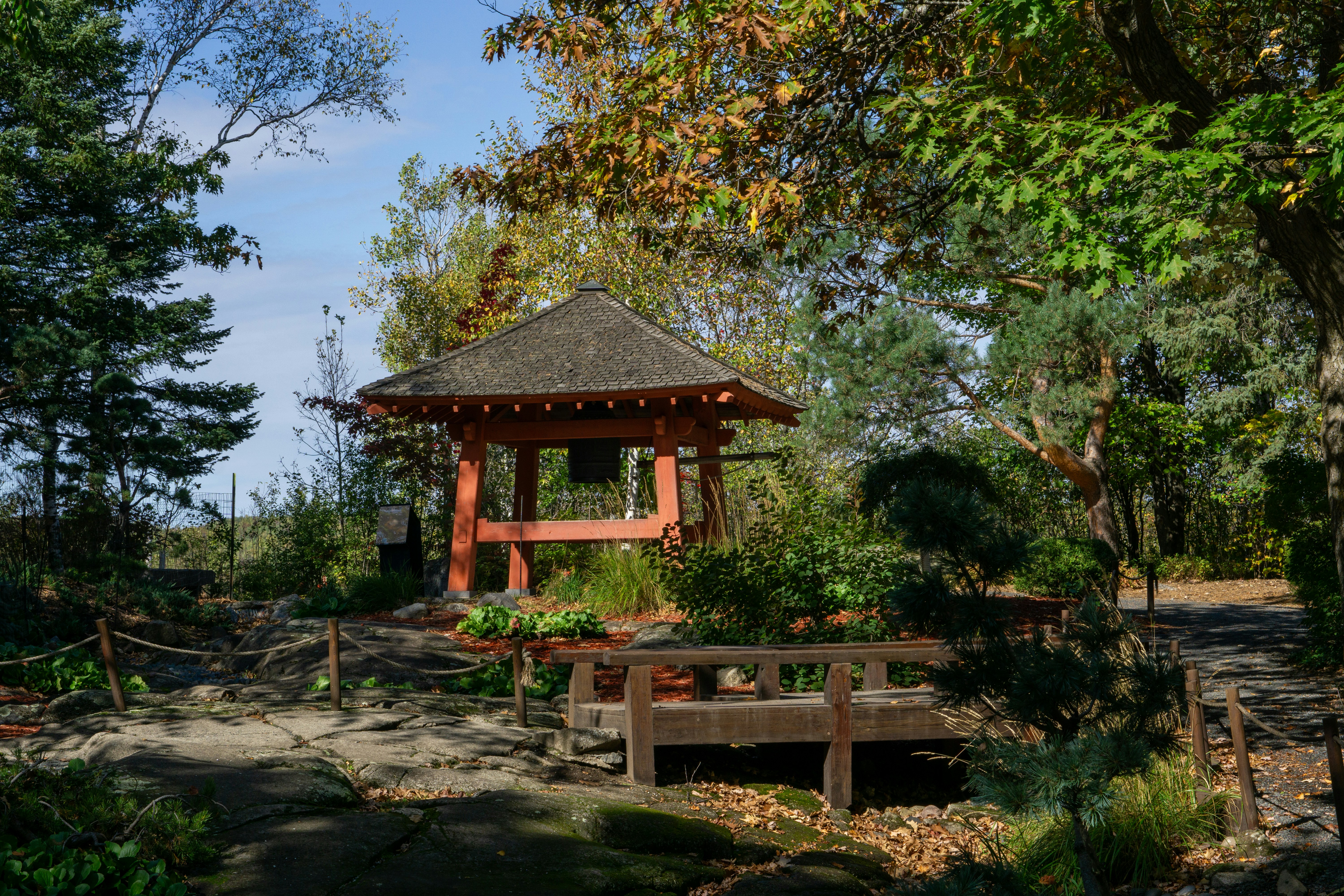 A traditional pavilion surrounded by lush greenery and autumn foliage, offering a tranquil escape in a natural setting.