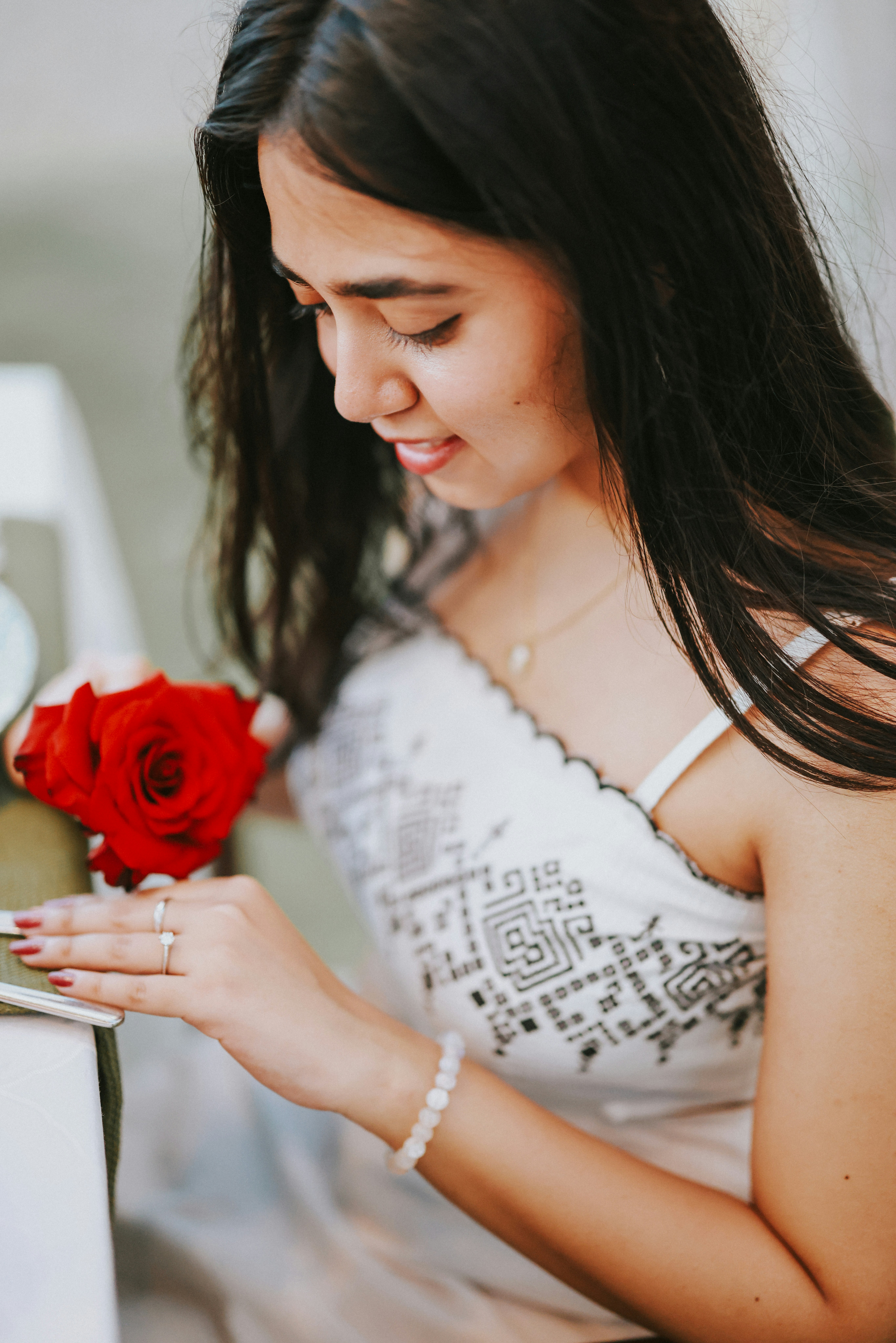 Young woman looking at phone with red rose