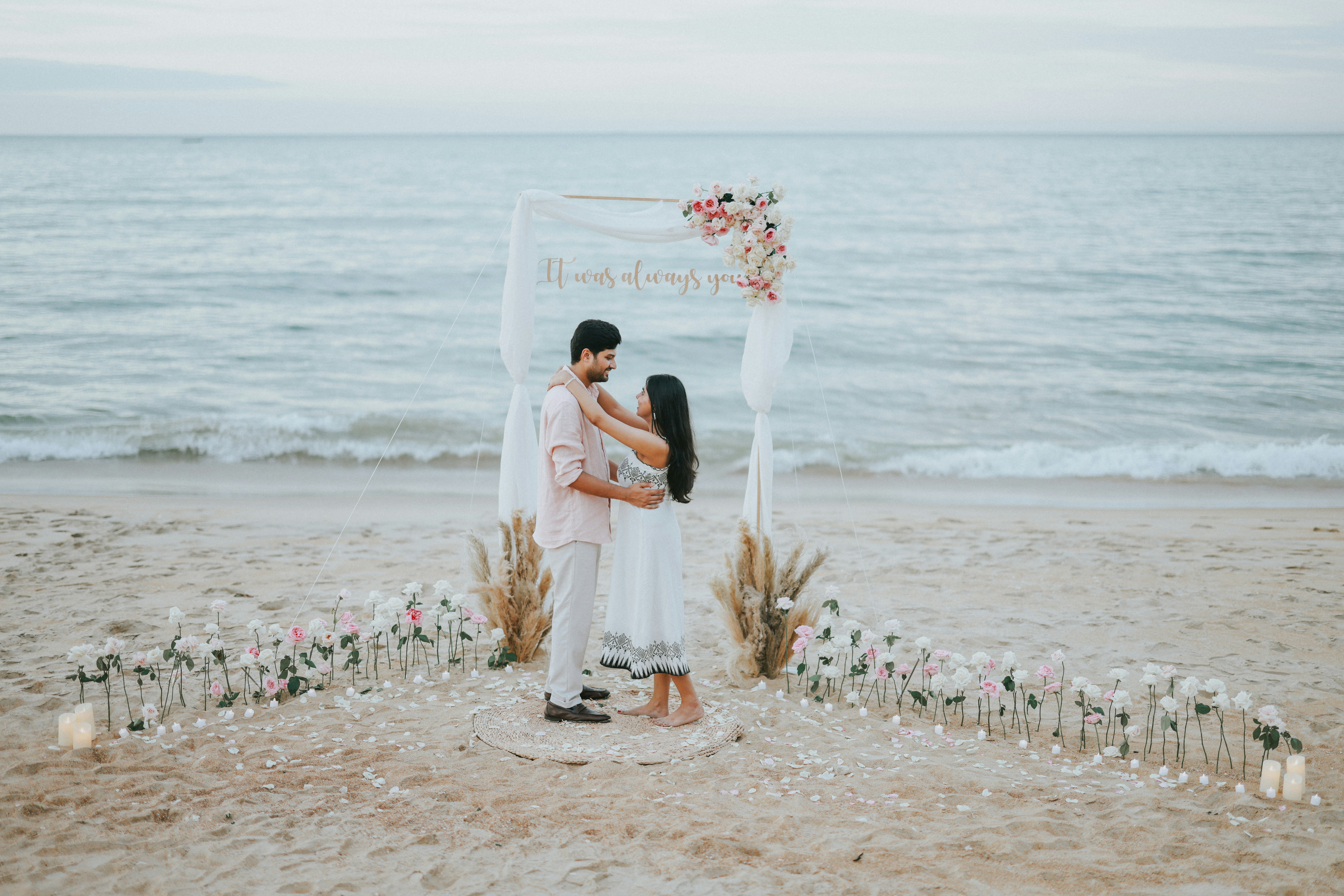 Couple embraces at a beach wedding ceremony setup