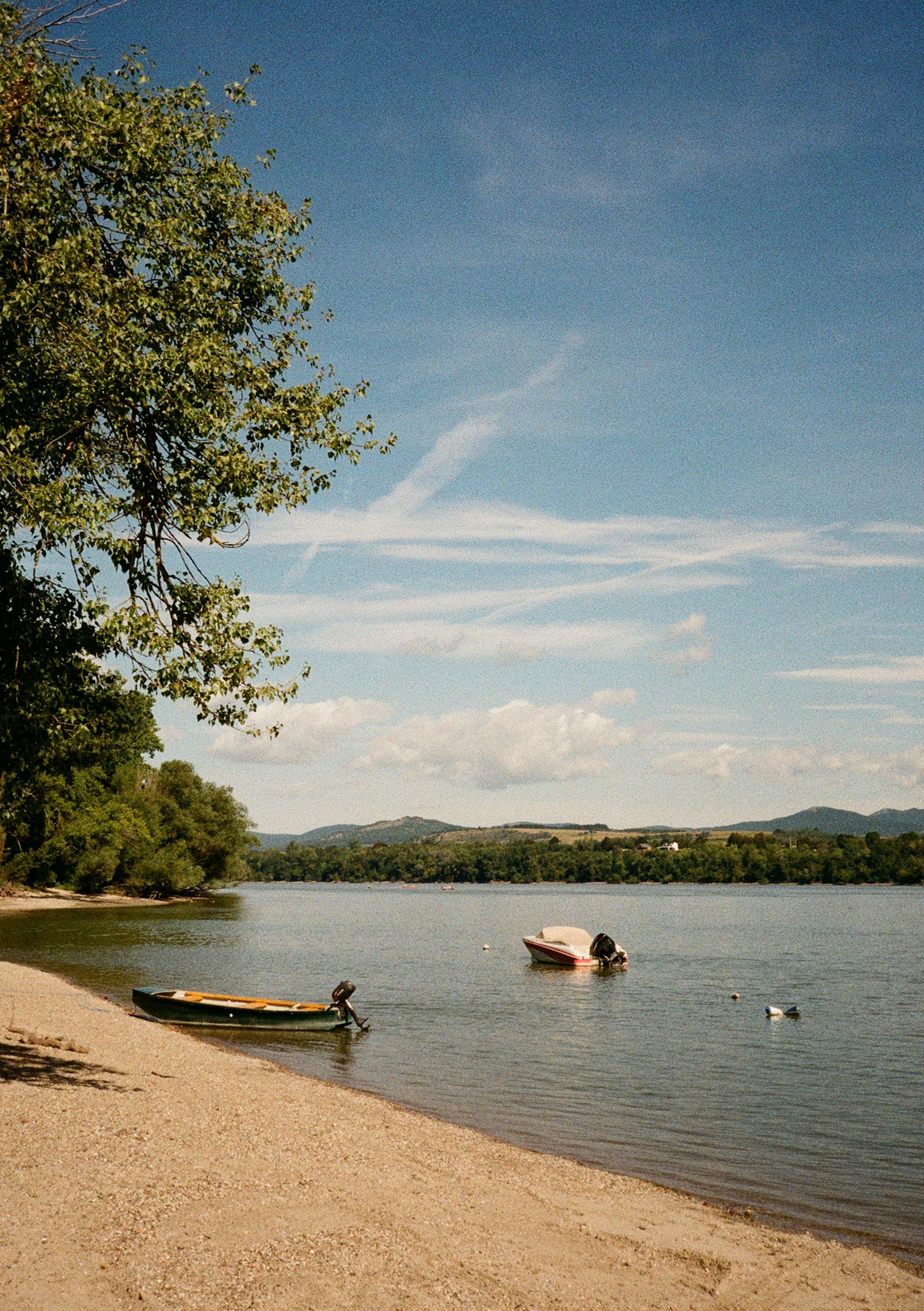 Two boats float on a calm river by the shore. photo – Free Beach Image ...