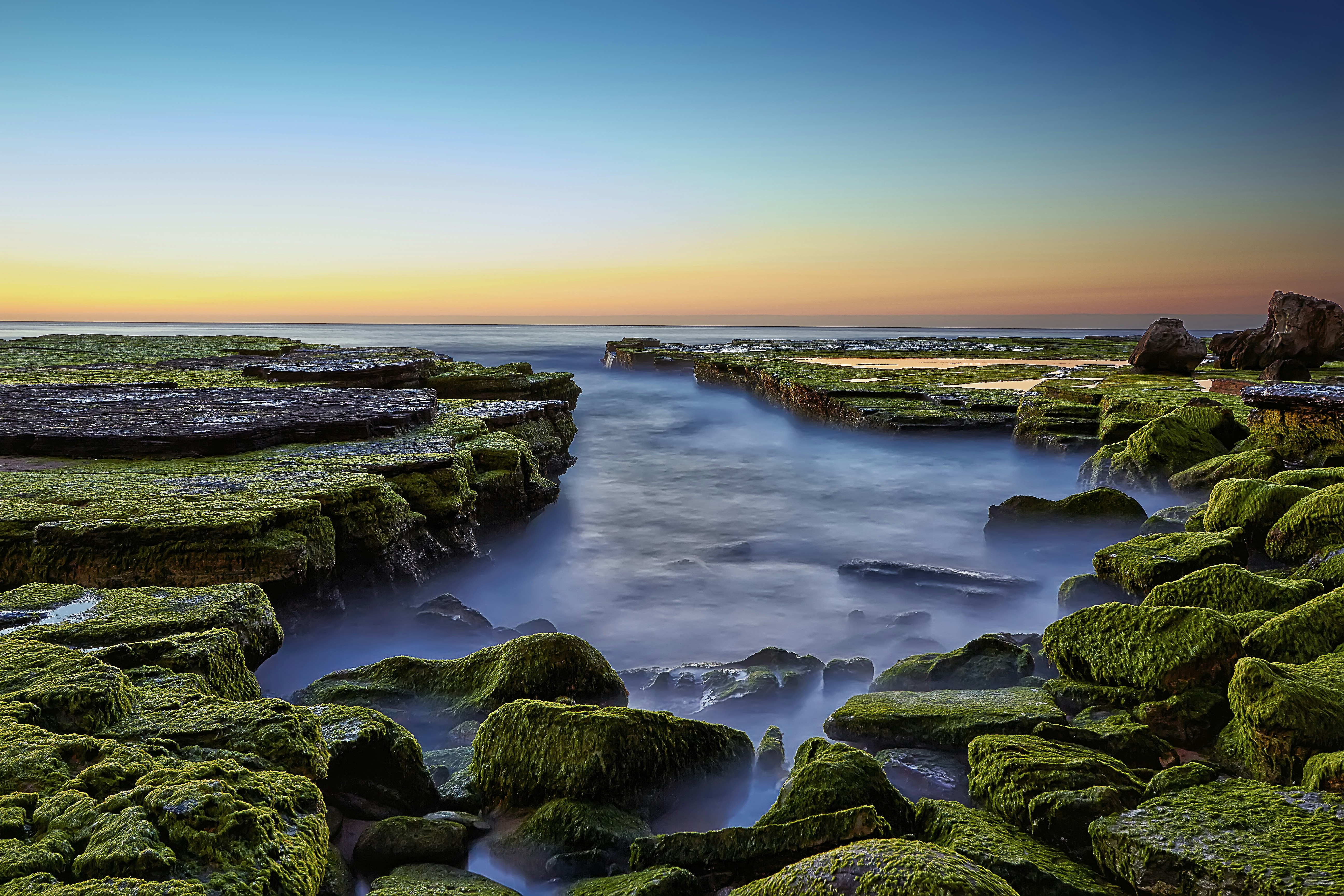 Moss-Cloaked Rocks Framing a Sunset Channel