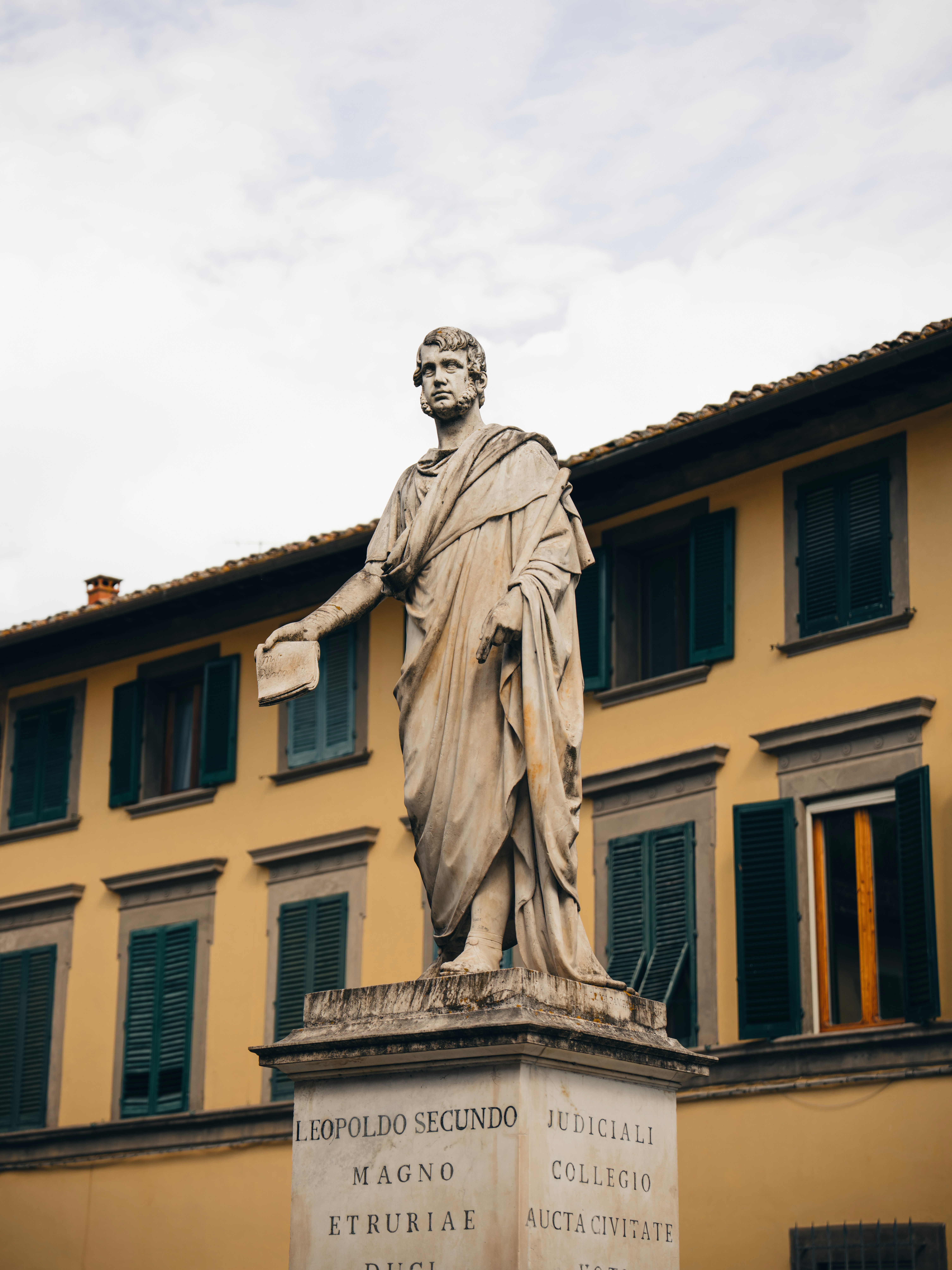 A marble statue stands in front of a yellow building.