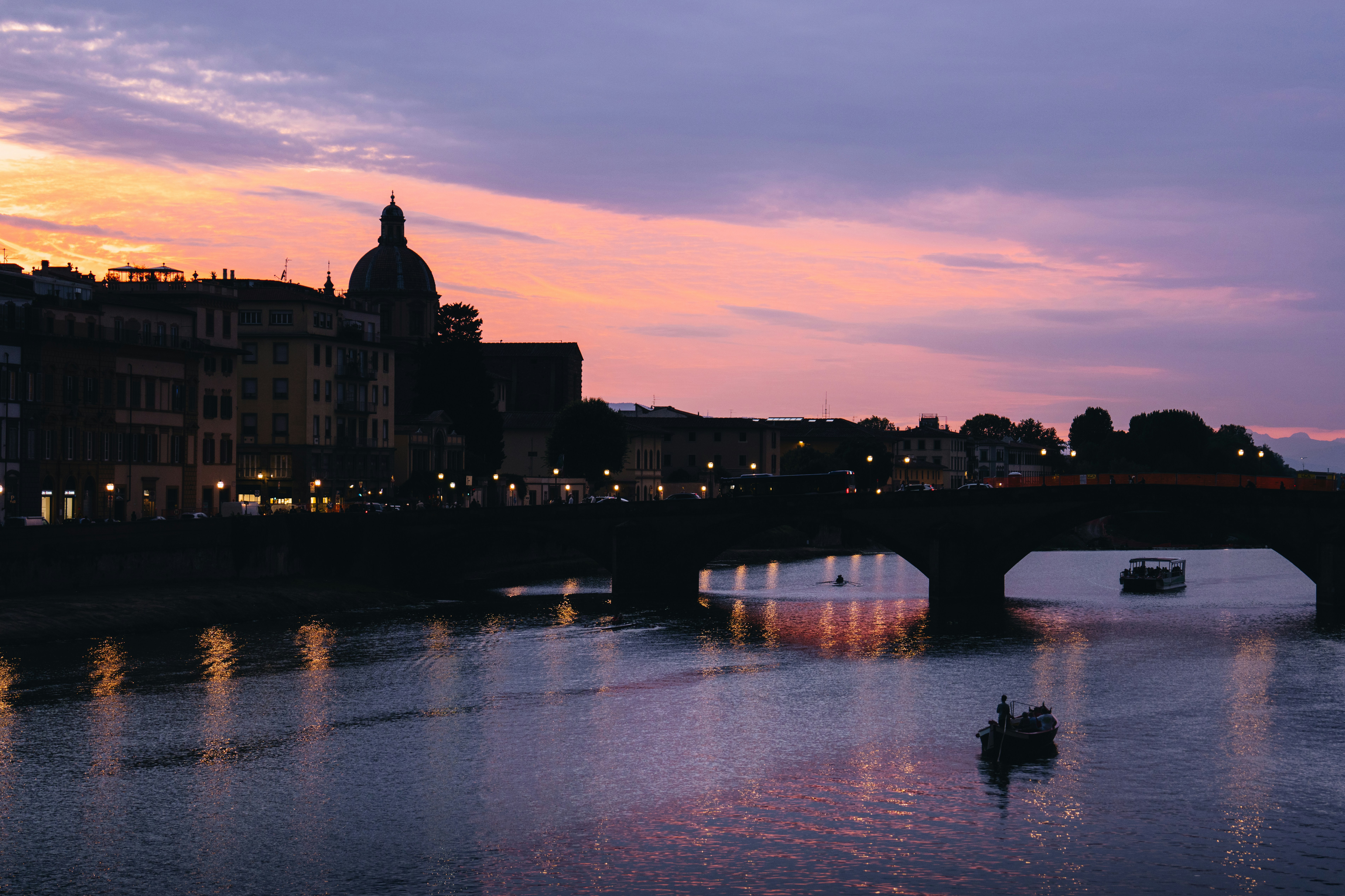 City skyline at dusk with a bridge and river.
