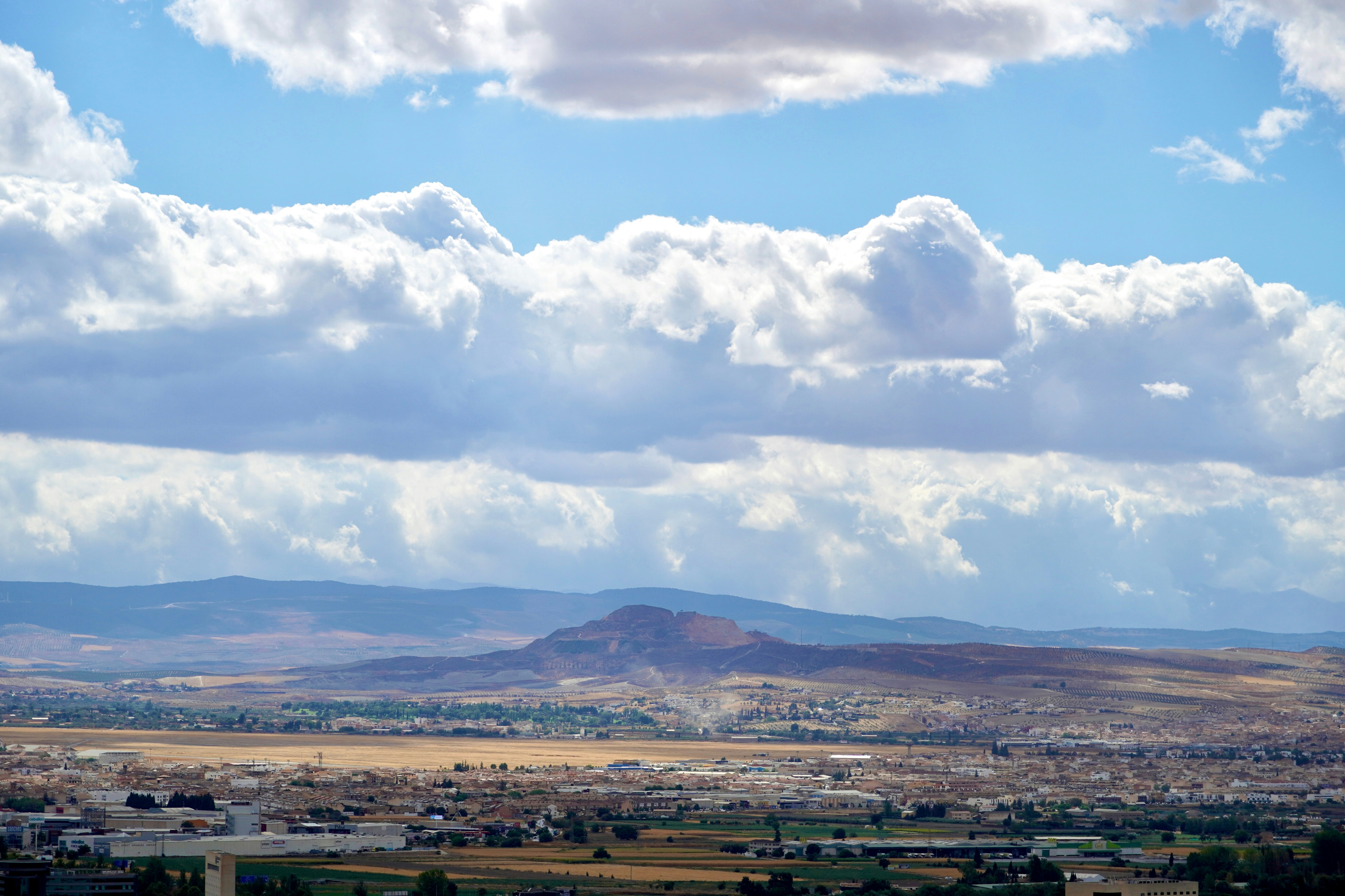 A vast landscape with rolling hills and dramatic clouds.