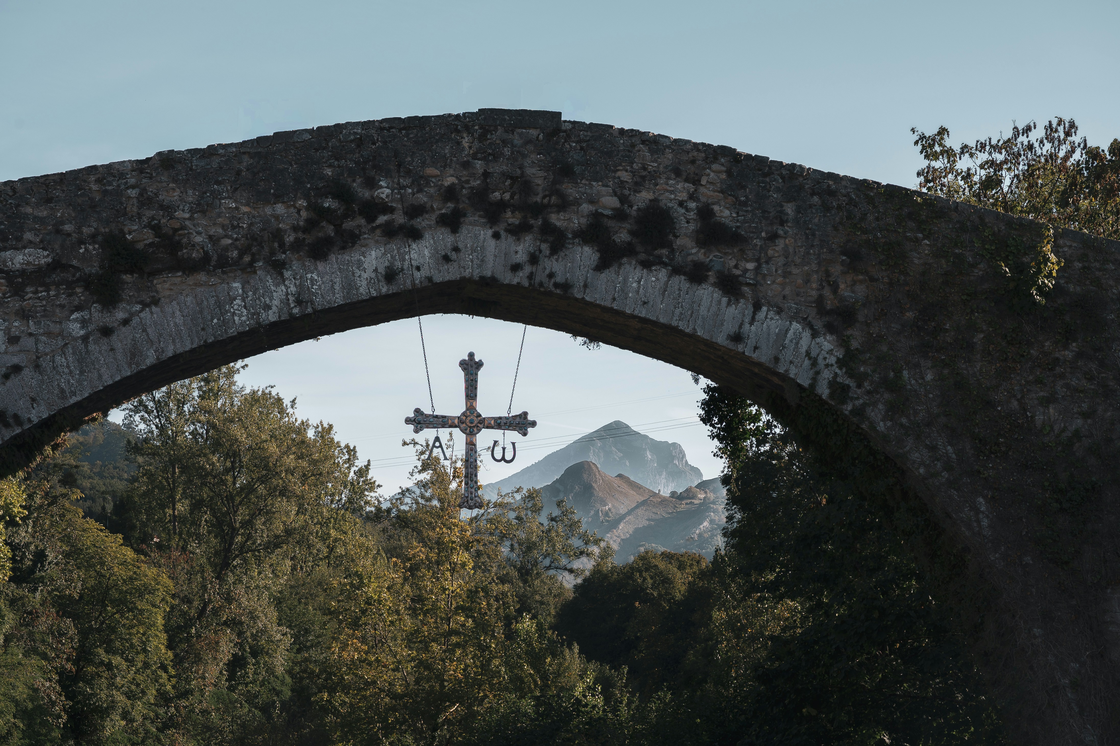 Stone bridge with cross and distant mountains